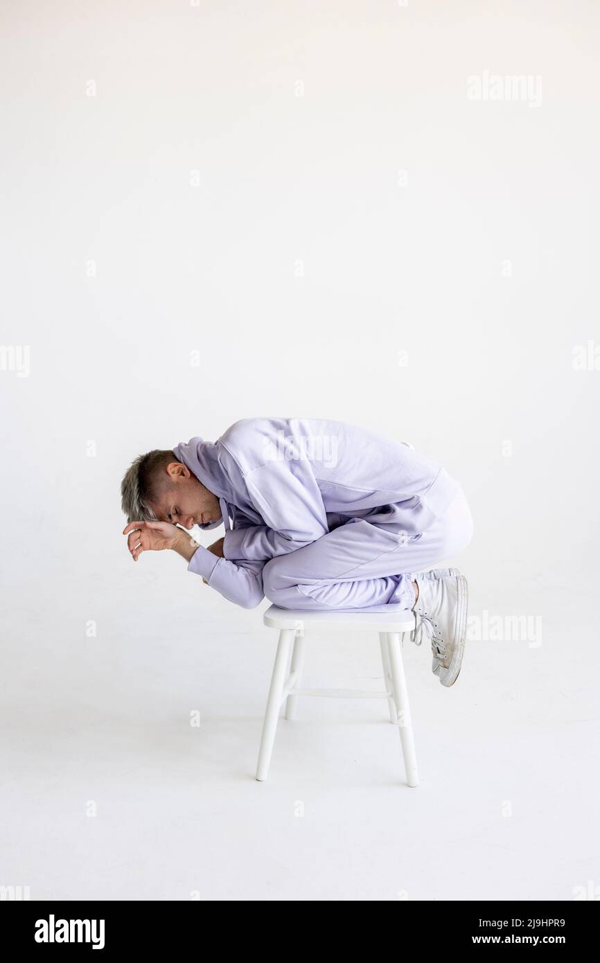 Depressed young man on chair against white background Stock Photo - Alamy