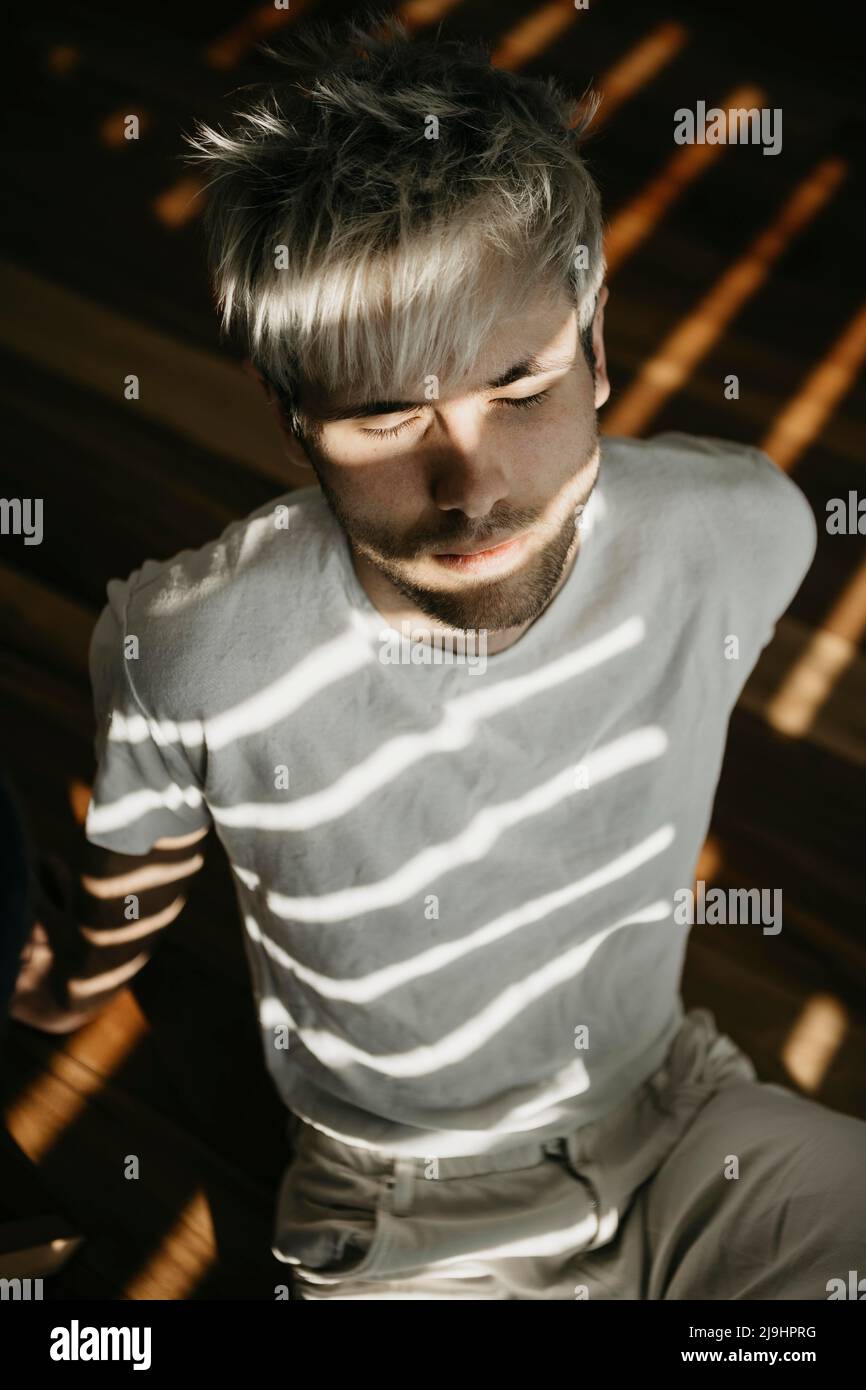 Young man enjoying sunlight sitting on floor Stock Photo - Alamy