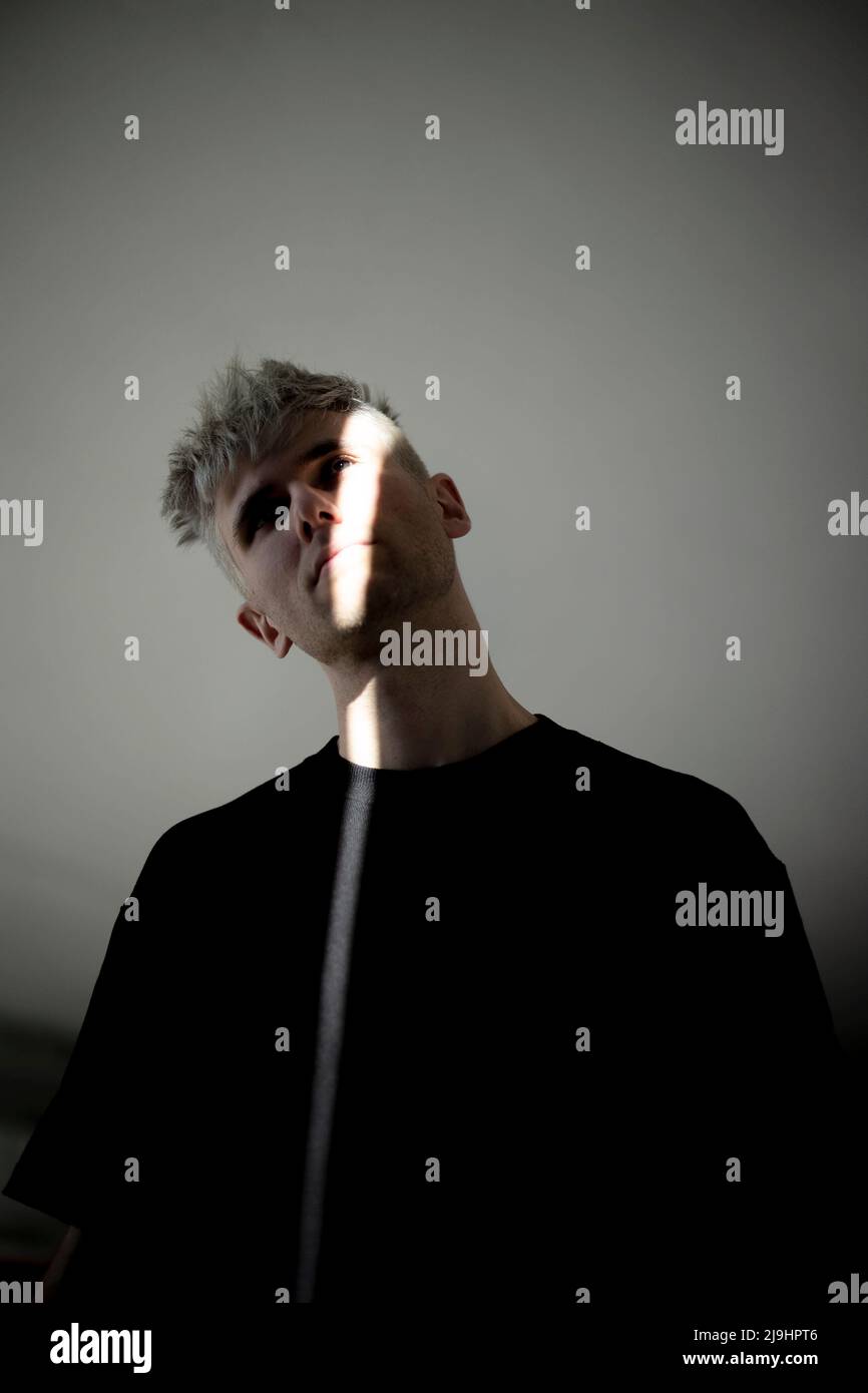 Smiling young man with beam of light on face against white background ...