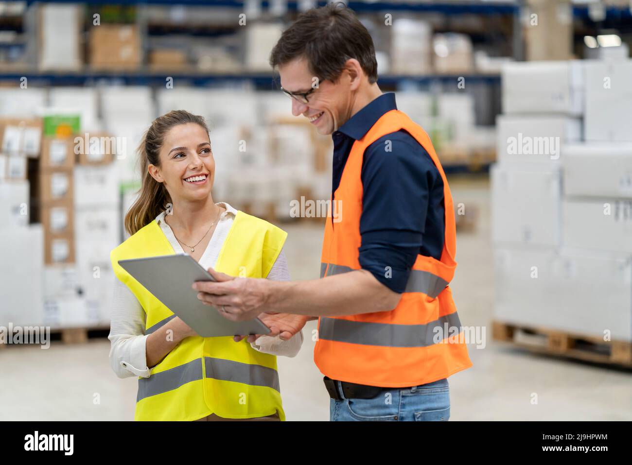 Smiling blue-collar workers discussing over tablet computer in ...