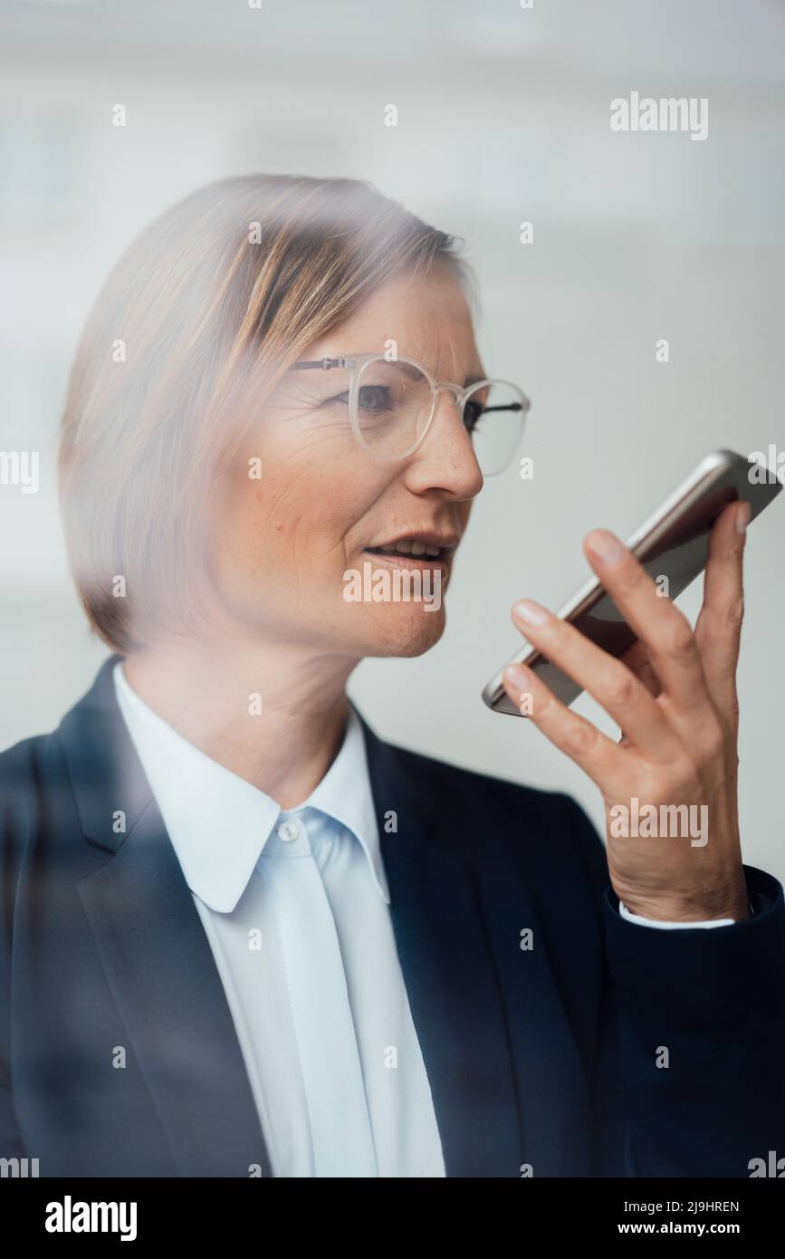 Businesswoman with brown hair talking through mobile phone speaker ...