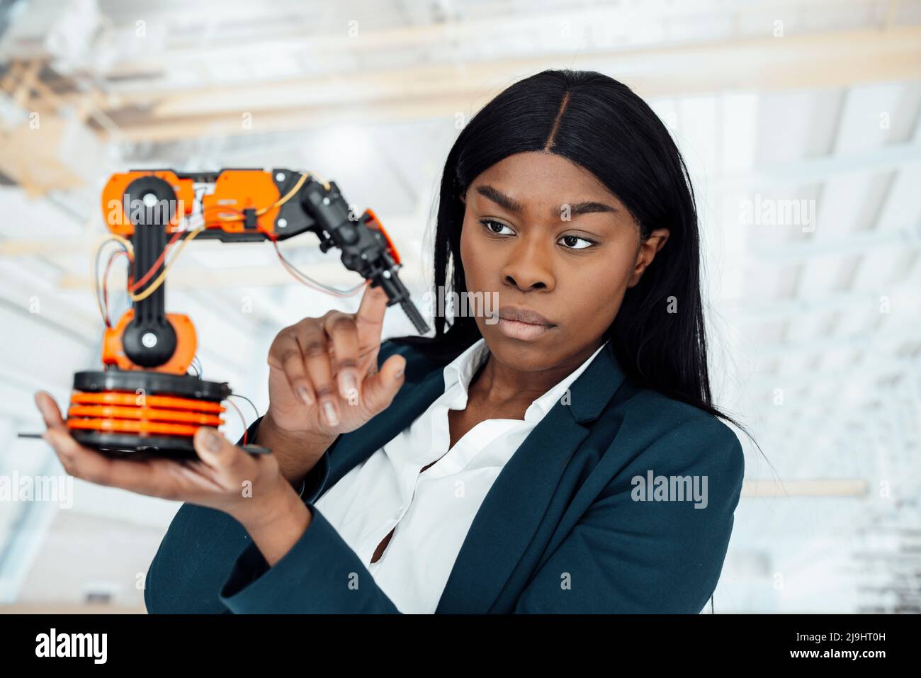 Engineer analyzing model of robotic arm in factory Stock Photo - Alamy
