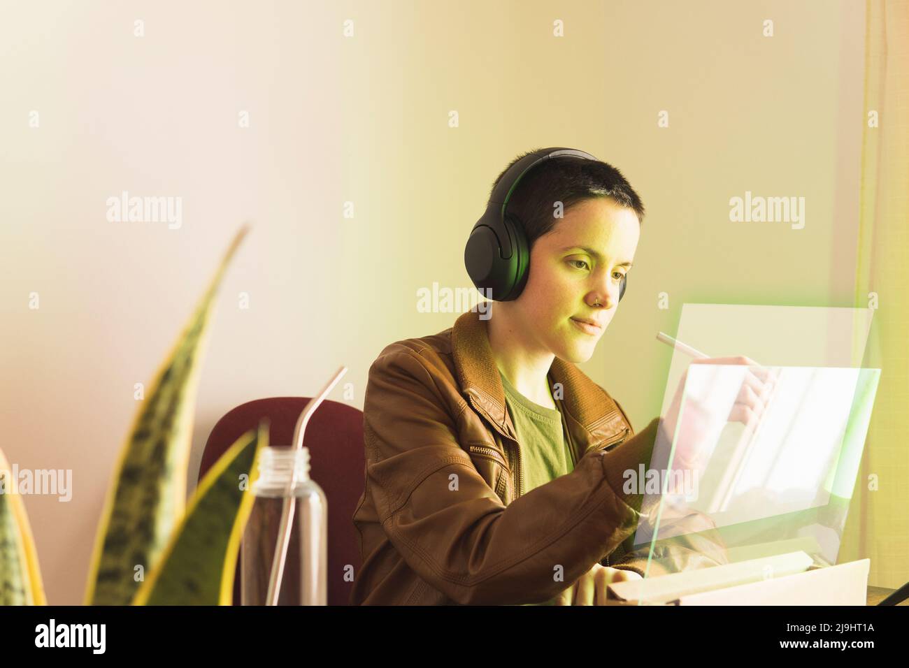 Freelancer wearing headphones writing on transparent screen with ...