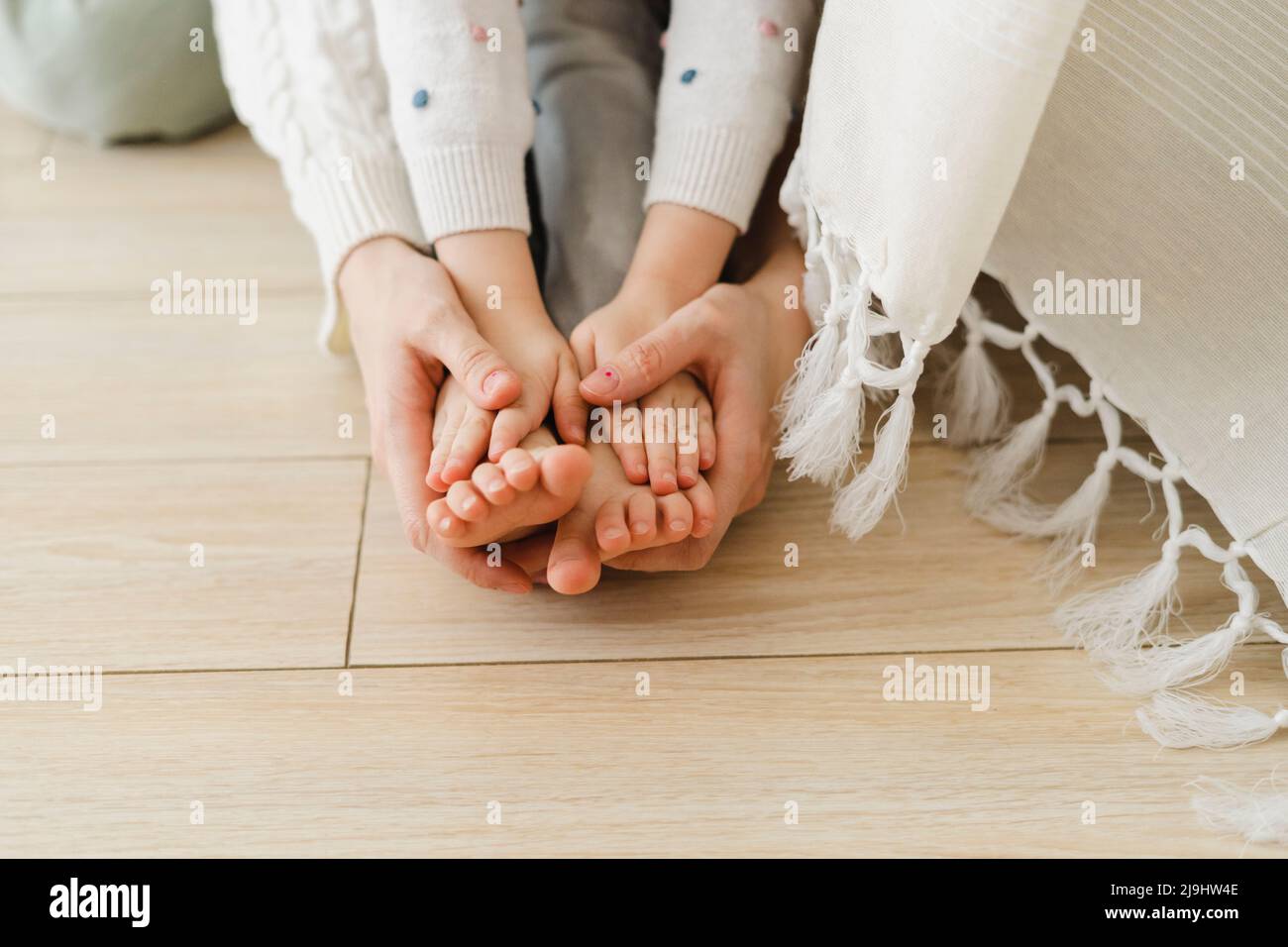 Mother's hand holding daughter's feet at home Stock Photo - Alamy