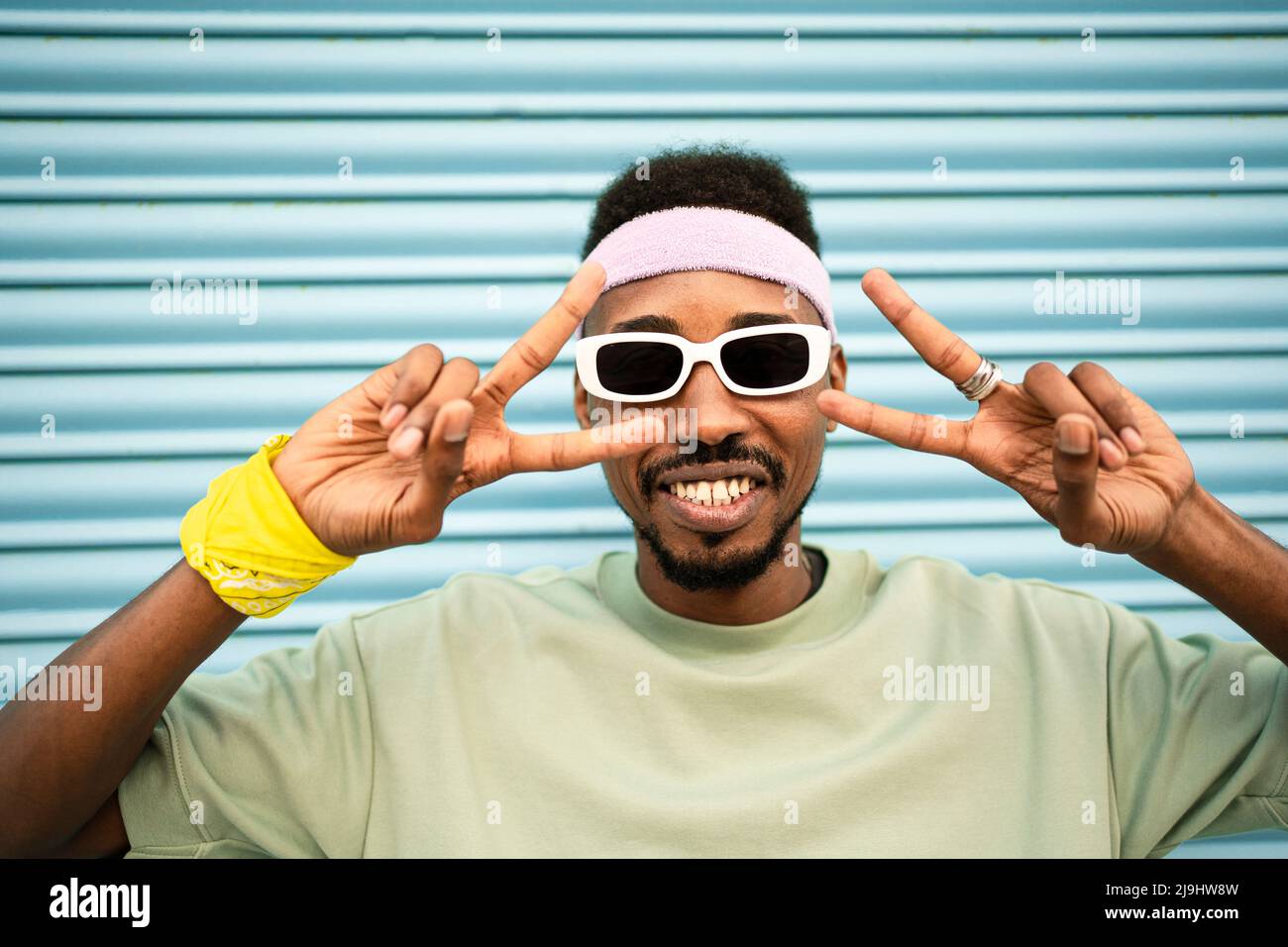 Happy man showing peace sign in front of blue shutter Stock Photo - Alamy