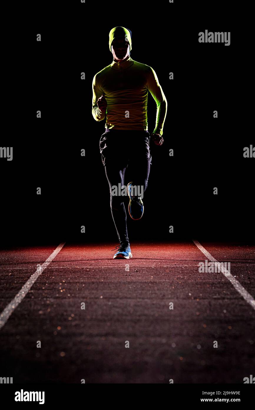 Young man jogging on running track at night Stock Photo - Alamy