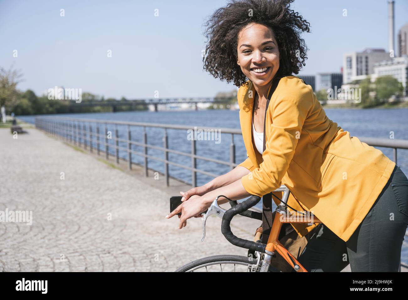 Happy commuter leaning on bicycle by River Main Stock Photo - Alamy
