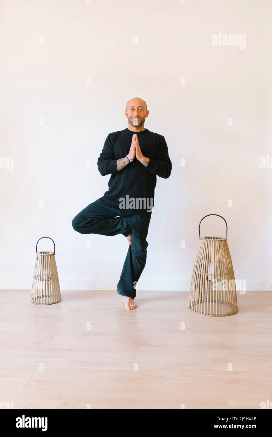 Man practicing tree pose in front of wall at yoga studio Stock Photo ...