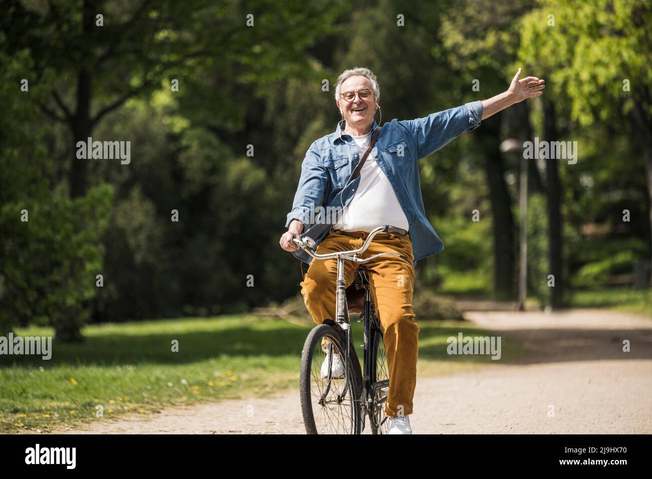 Happy senior man with arms raised enjoying bicycle ride at park Stock ...