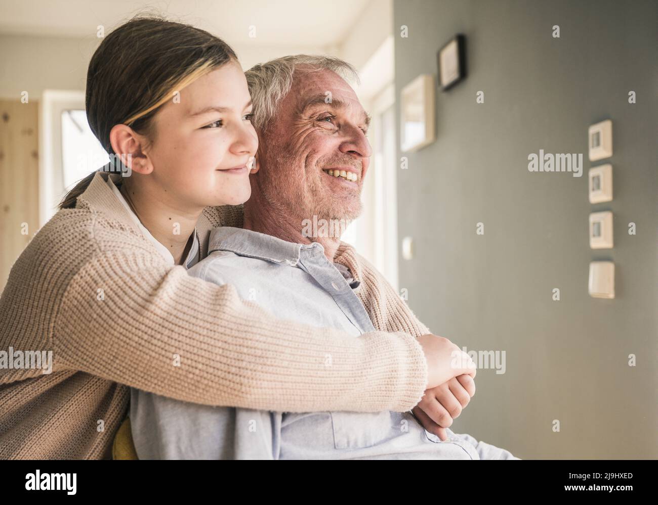 Smiling girl hugging grandfather from behind at home Stock Photo - Alamy
