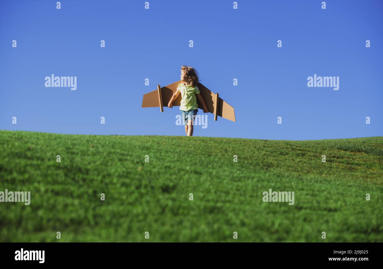 Child boy like a pilot with toy wings against blue sky. Kids freedom ...
