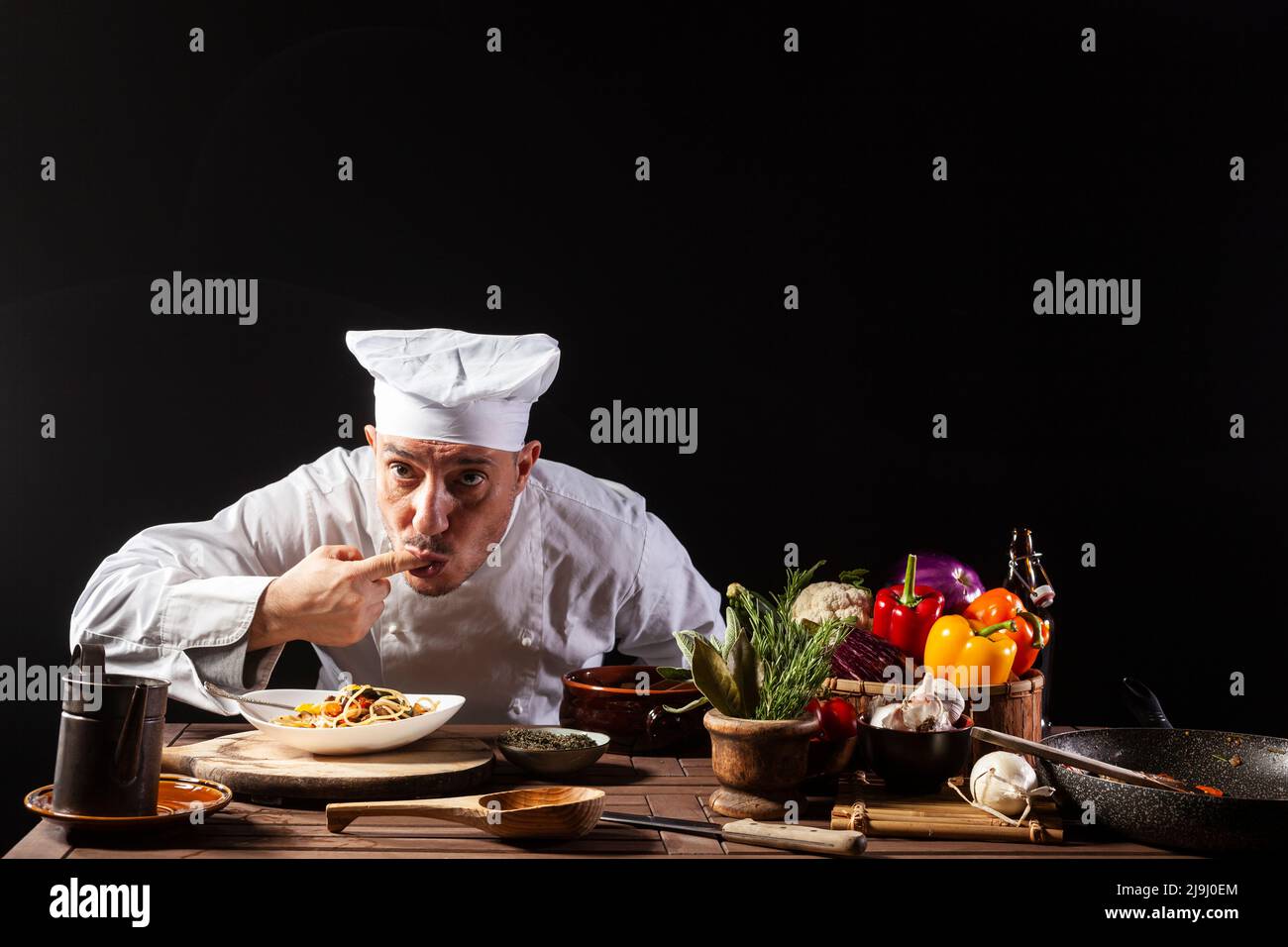 Male chef in white uniform preparing spaghetti with vegetables and ...