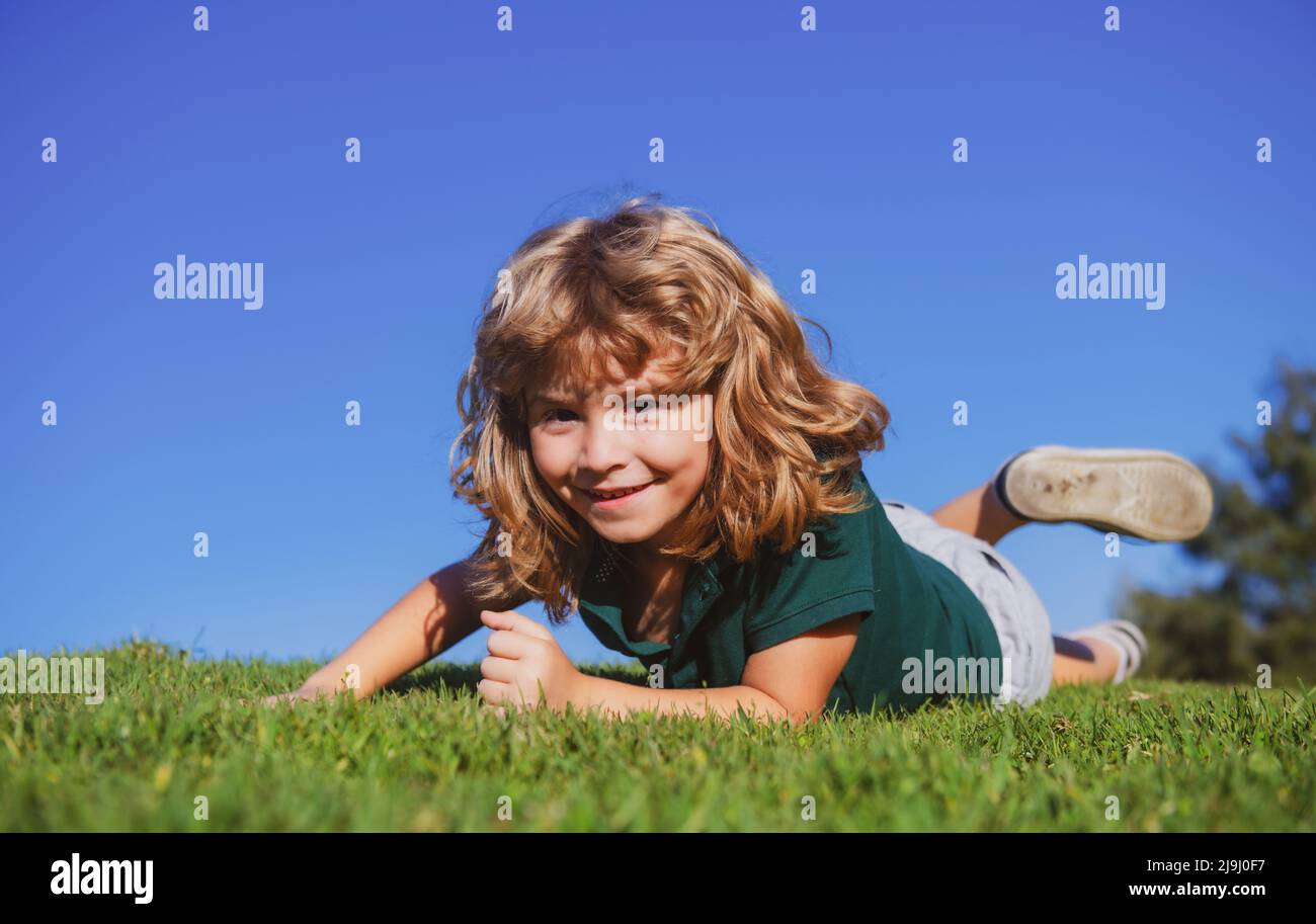 Portrait of a happy little boy laying on the grass in the park. Outdoor ...