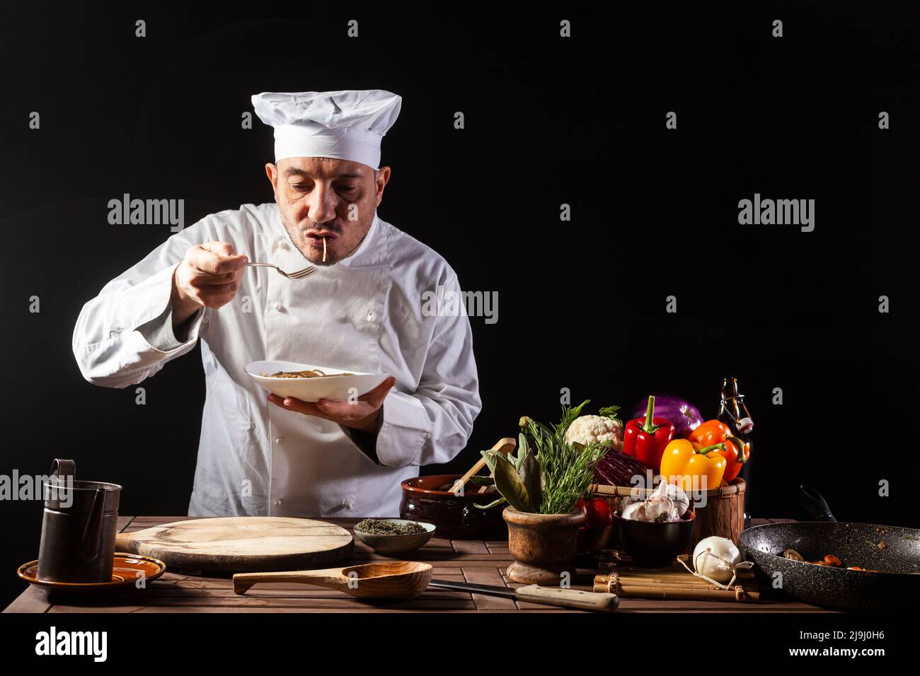 Male chef in a restaurant kitchen wearing white uniform tasting ...