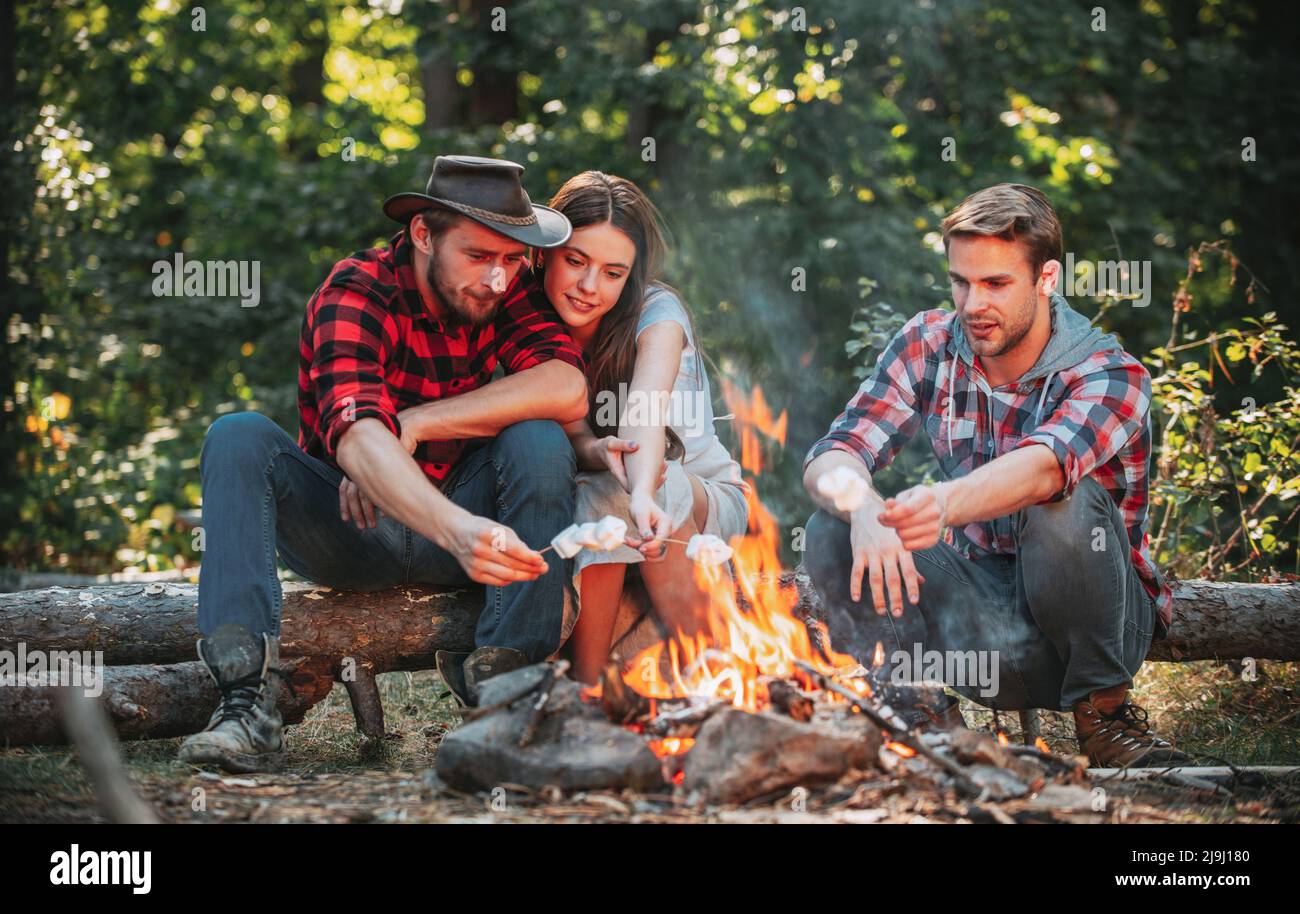 Group of backpackers relaxing near campfire. Friends spend leisure ...