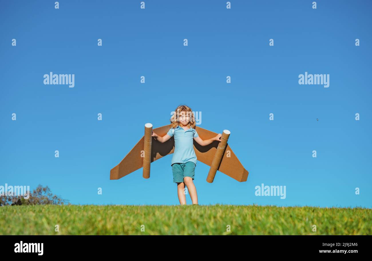 Kid with toy jetpack outdoor. Child playing in green spring field with ...