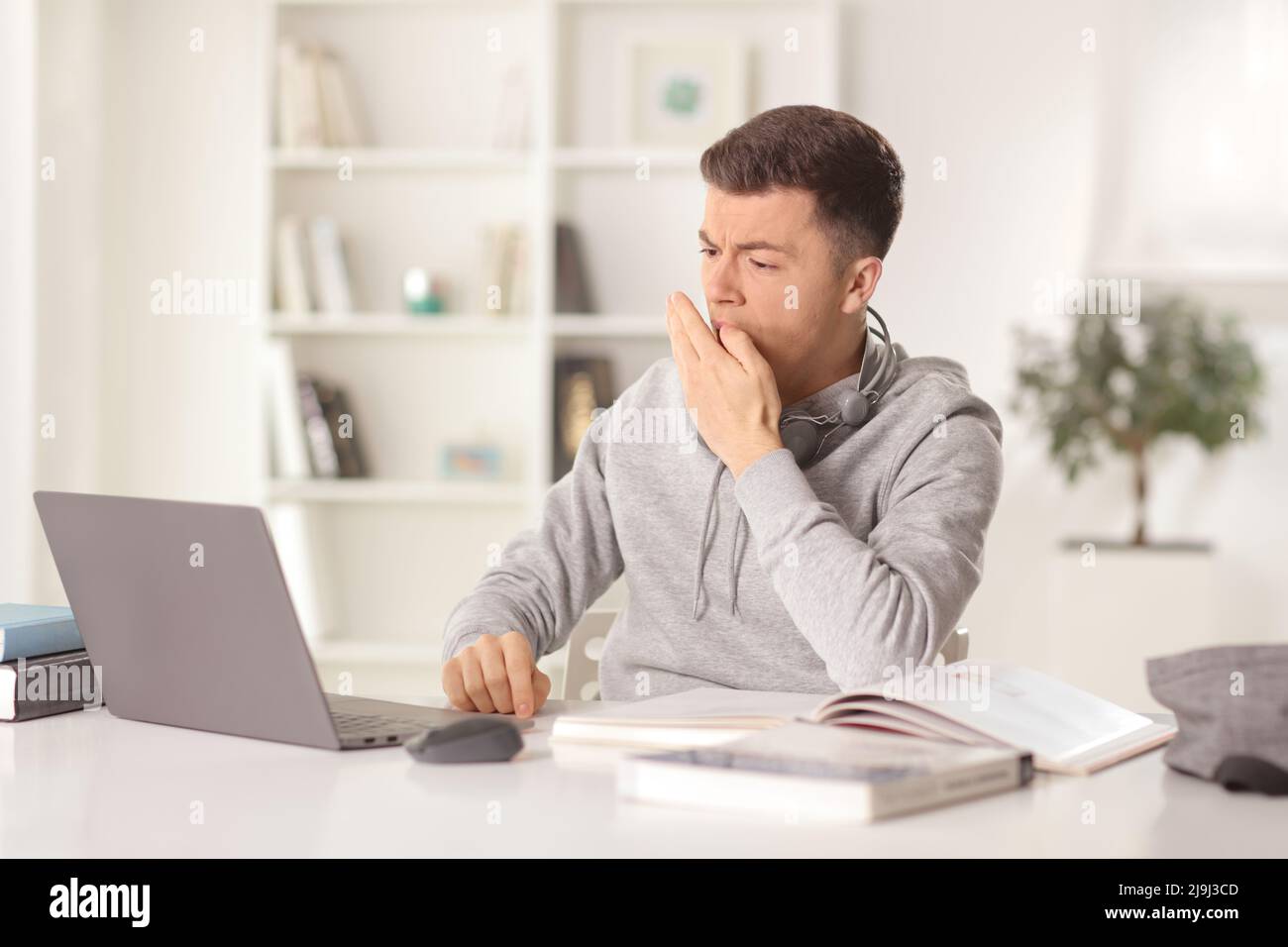 Guy sitting in front of a laptop computer at home and yawning Stock ...