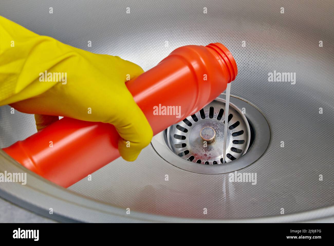 Person's hand in a yellow rubber glove pours pipe cleaner down the ...