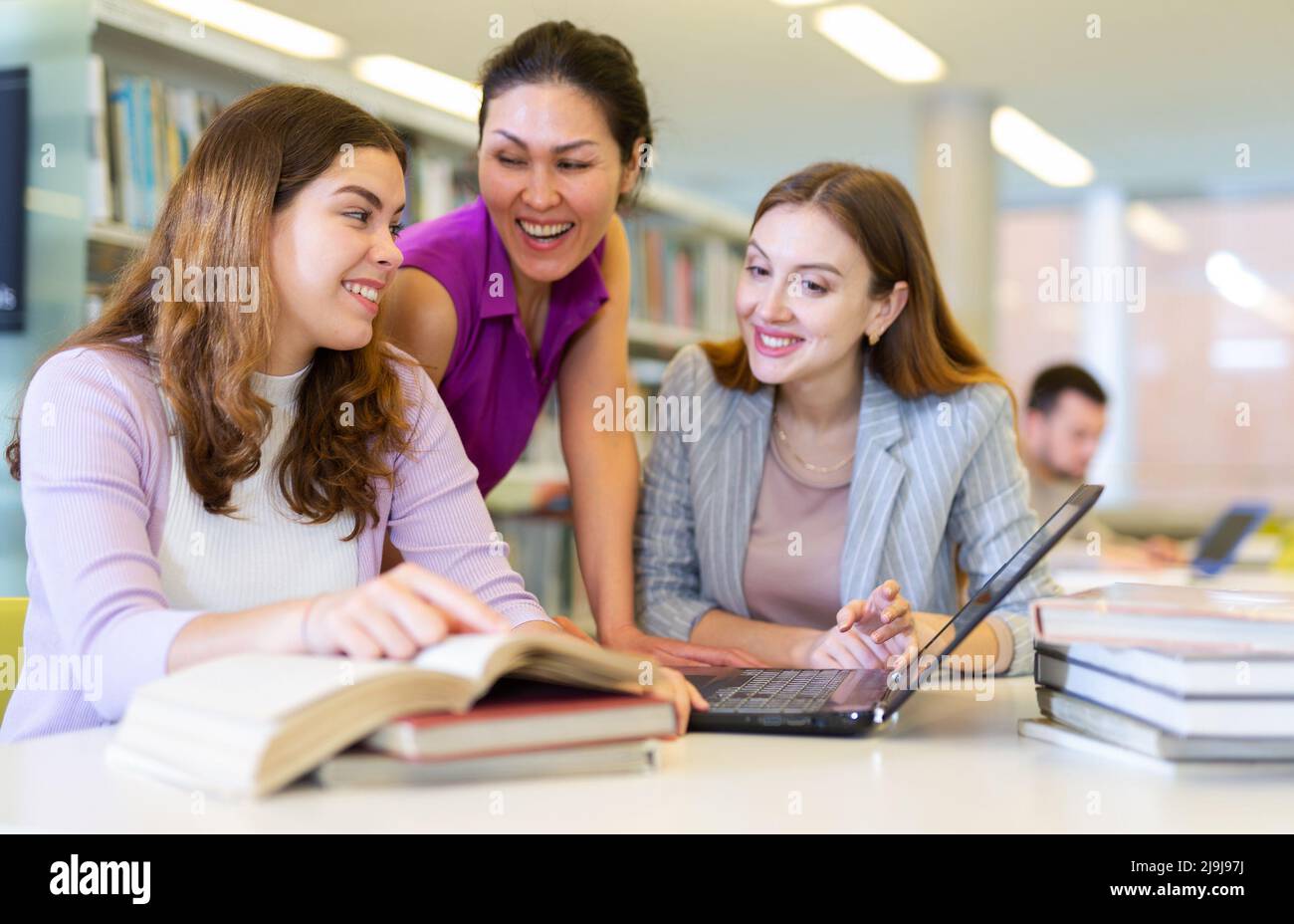 Three girls students, preparing for classes in the library Stock Photo ...