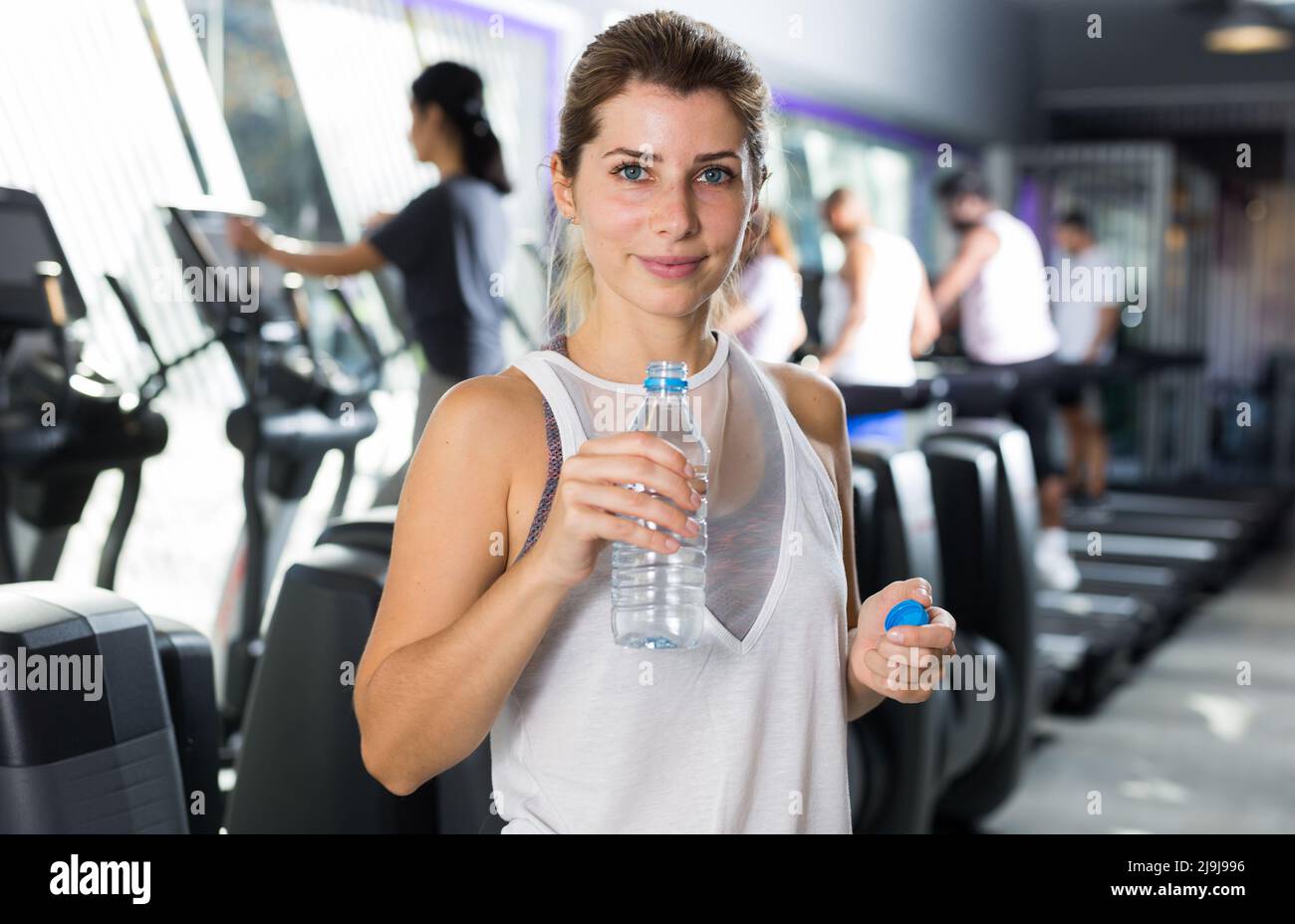 Woman standing with drinking water in gym Stock Photo - Alamy