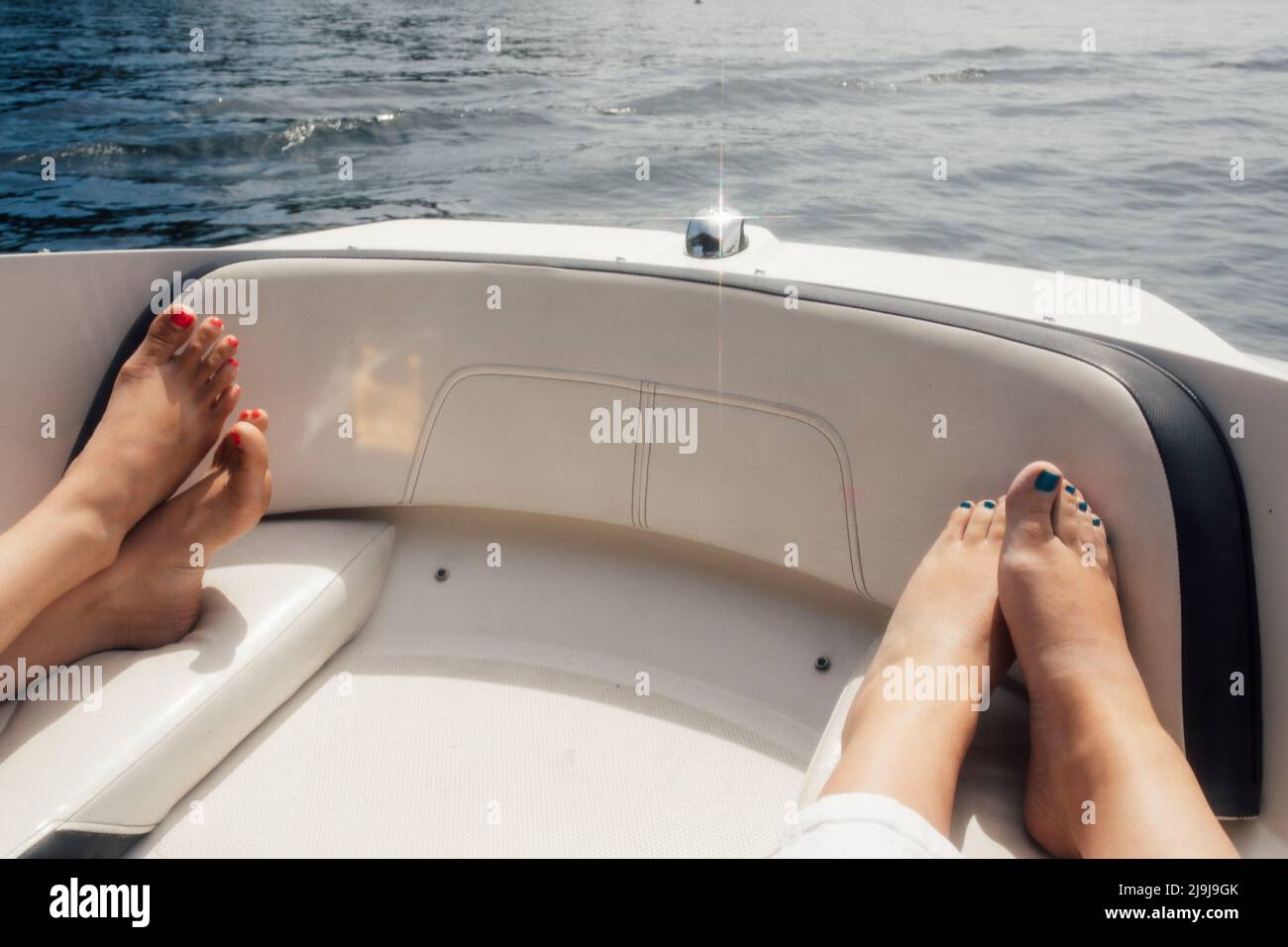 two sets of lady feet resting on bow of boat Stock Photo - Alamy