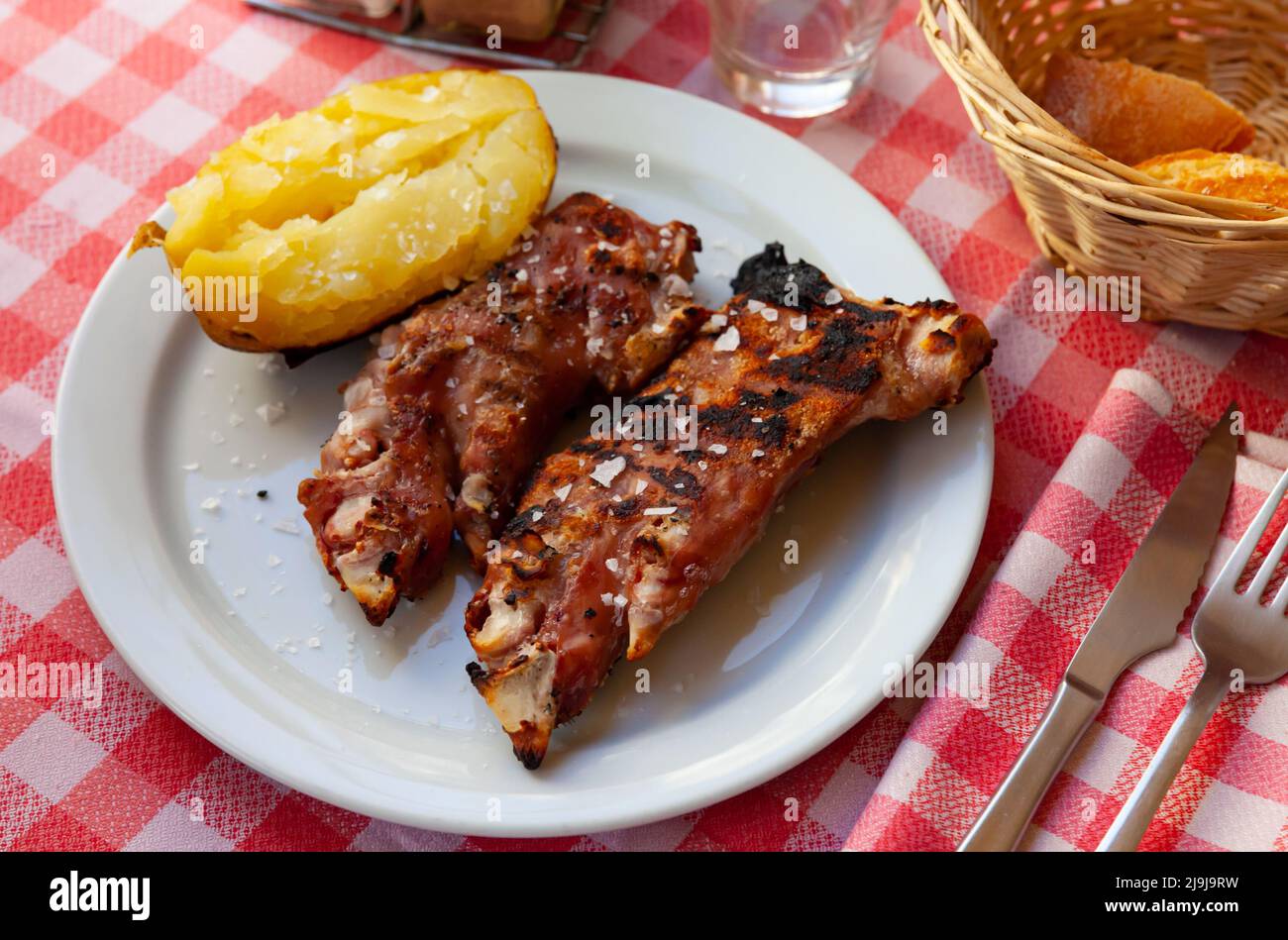 Spicy pig trotters grill with baked potato Stock Photo - Alamy