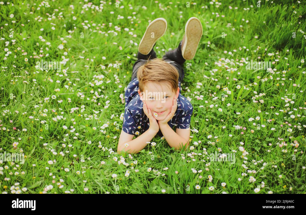 Spring boy. Happy childhood. Smiling kid lying on grass. Dreaming ...