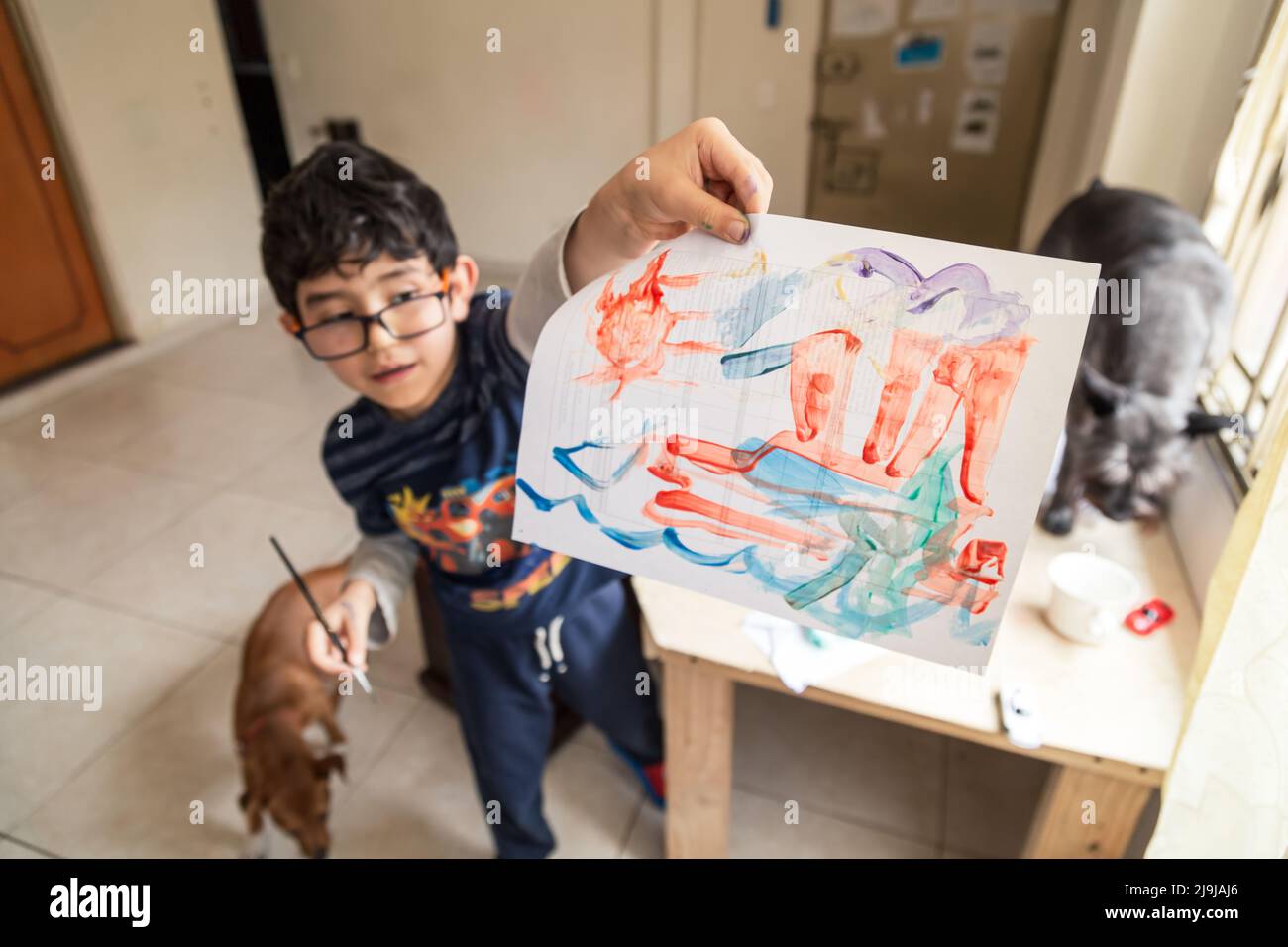 child painting with paints and colored pencil laughing making a drawing ...