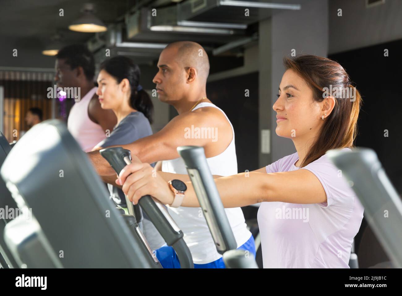 People having running elliptical trainer class in club Stock Photo - Alamy