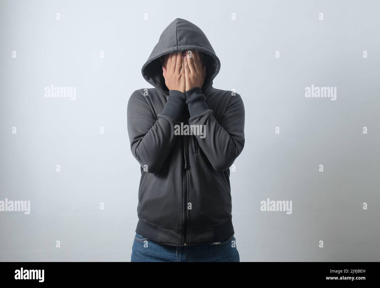 portrait of hooded man covering his face using hands Stock Photo - Alamy