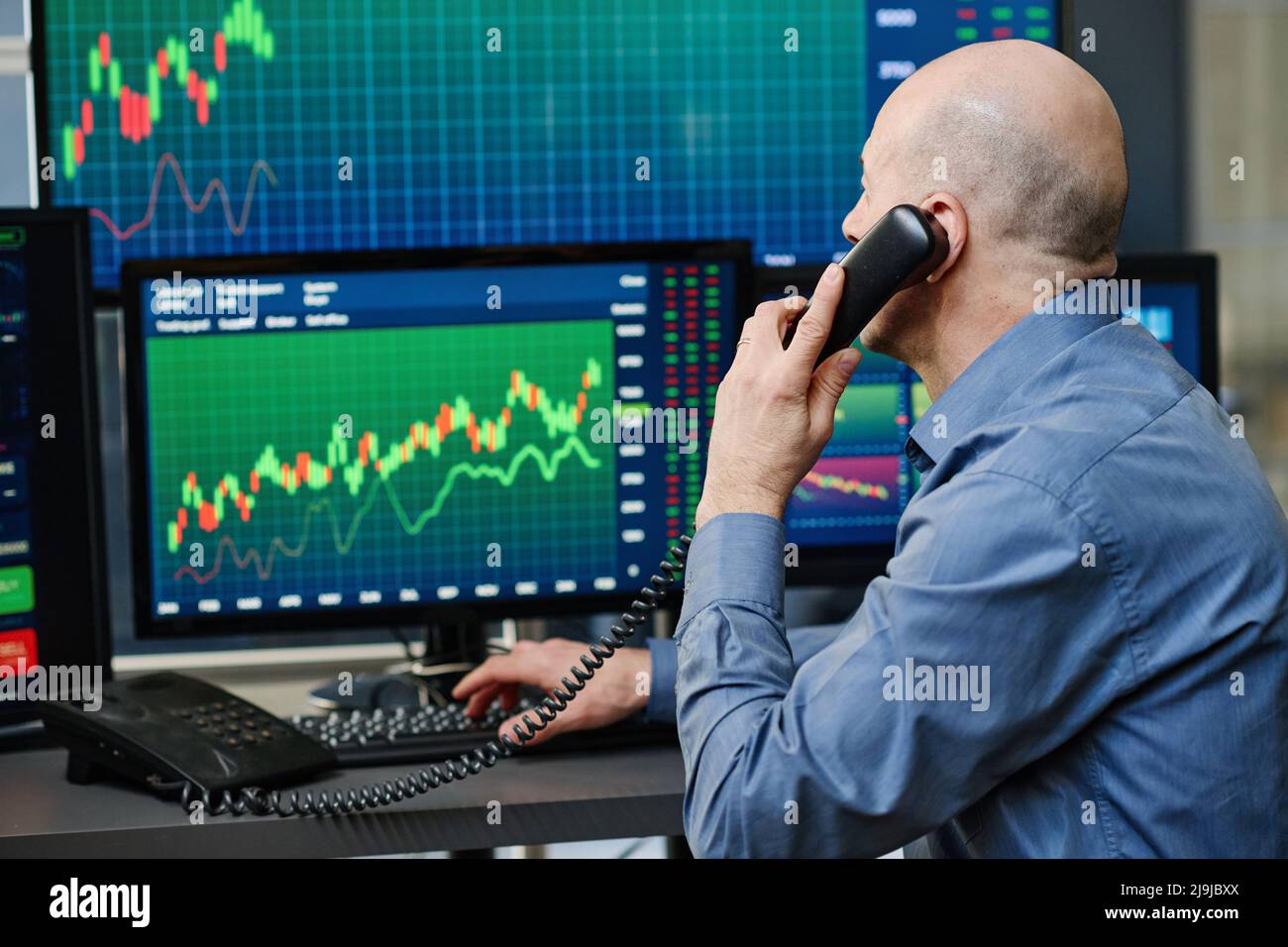 Business broker sitting in front of computer monitors looking through ...