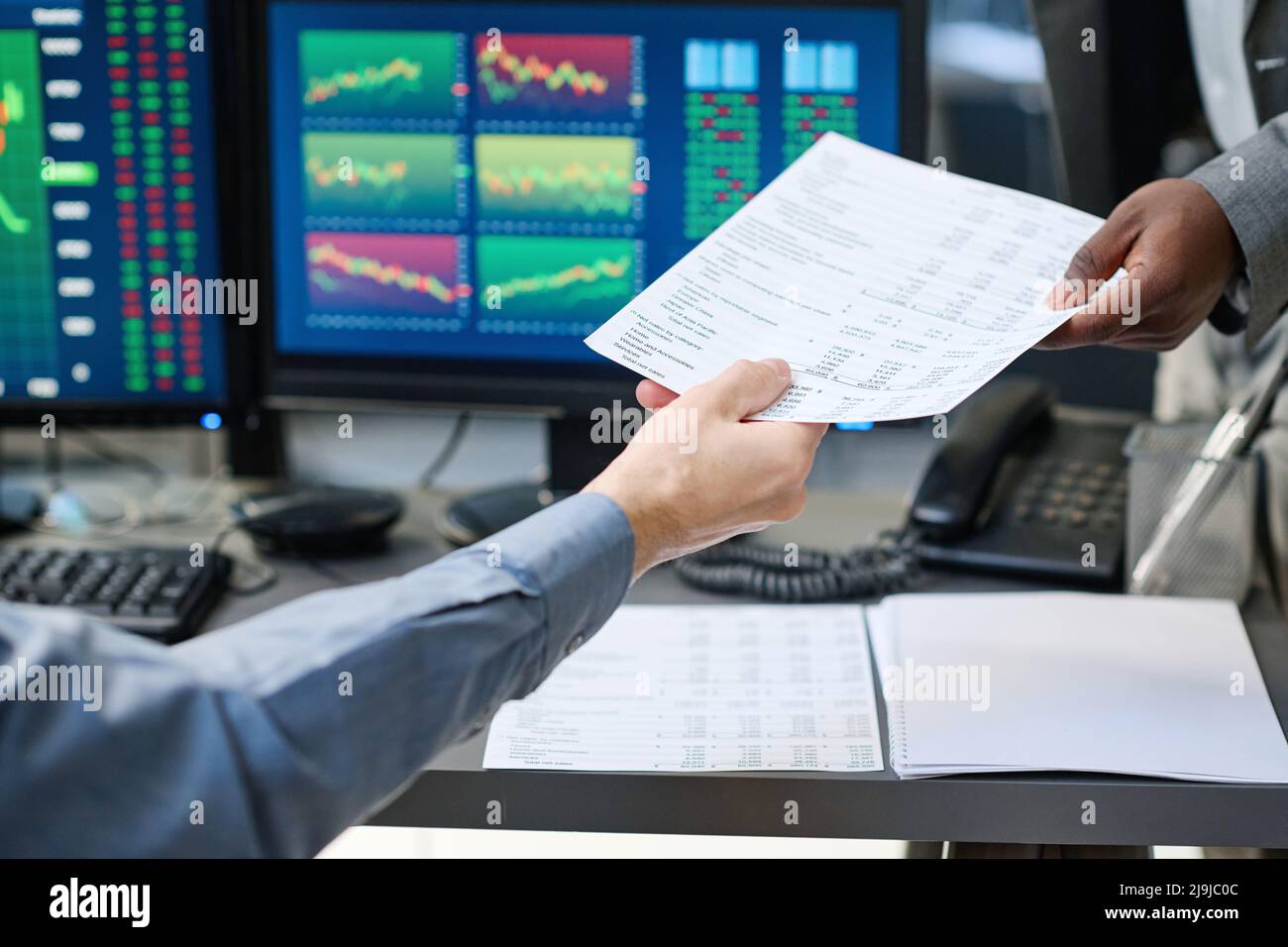 Unrecognizable busy stock trading specialist sitting in front of ...