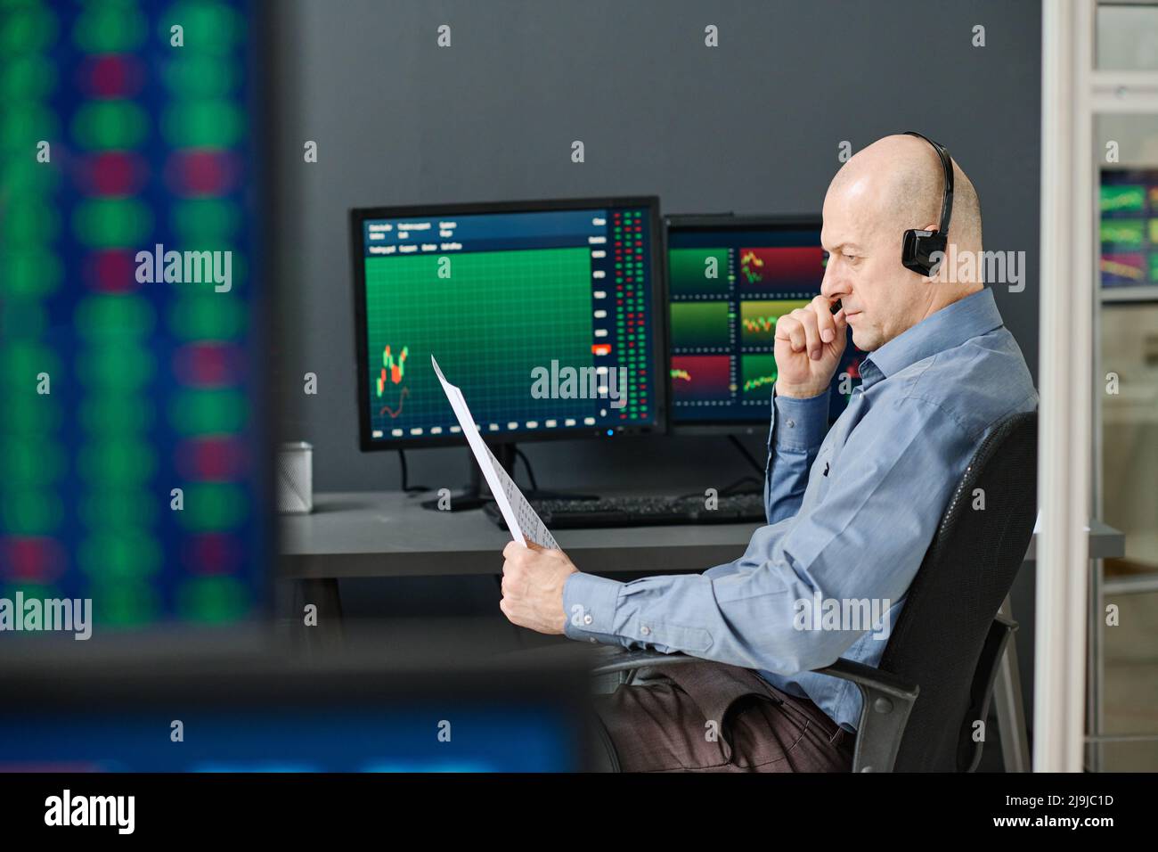 Mature professional Caucasian stock data analyst sitting at desk in ...