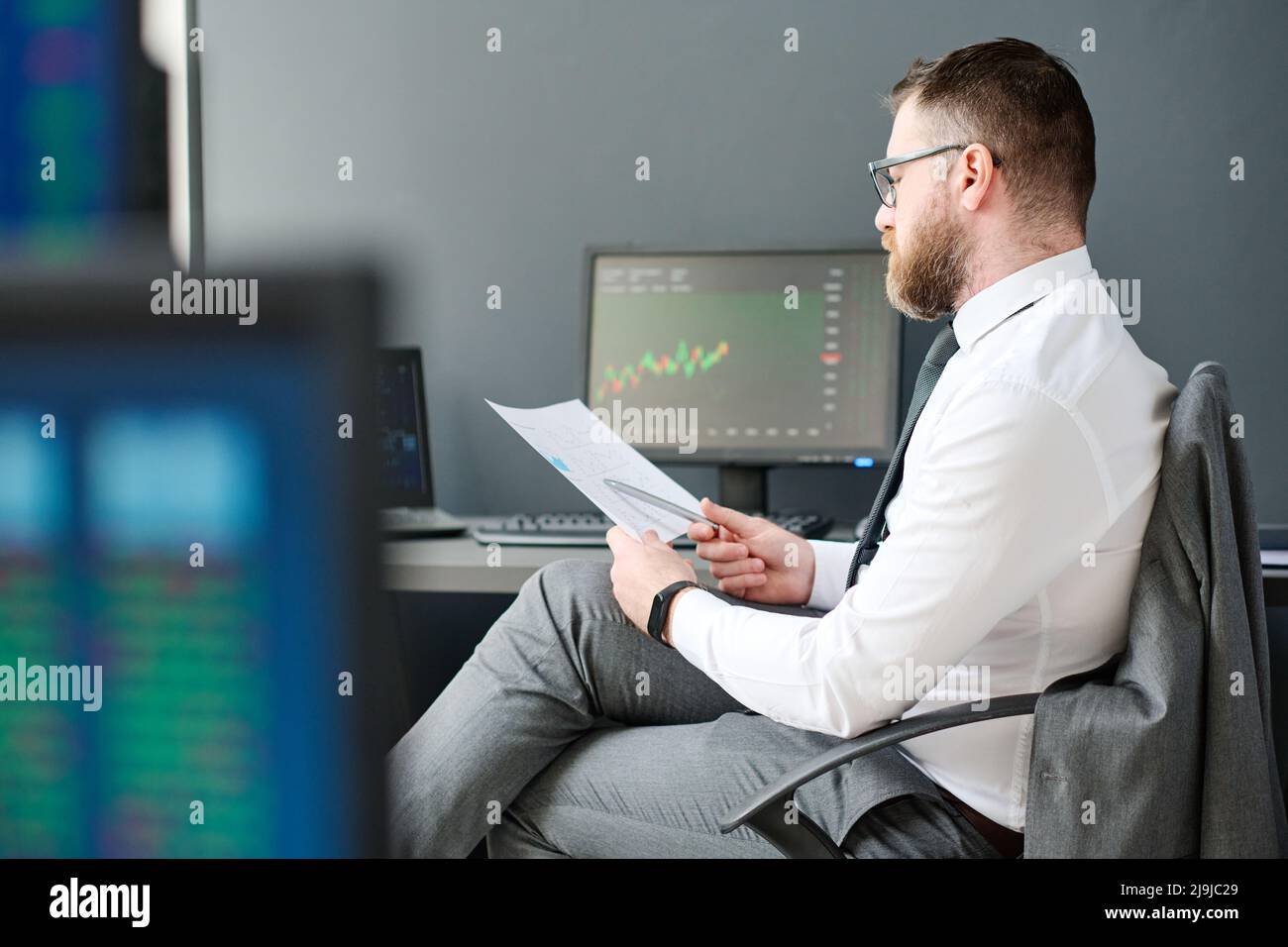 Young adult man with beard on face sitting at desk in office working on ...