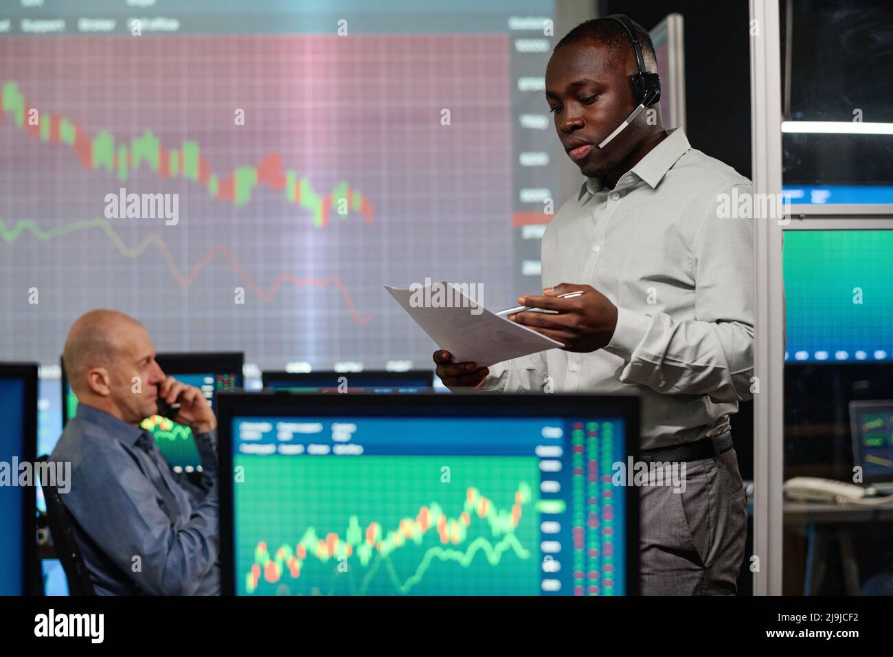 Modern professional business broker holding documents working in evening in modern office ...