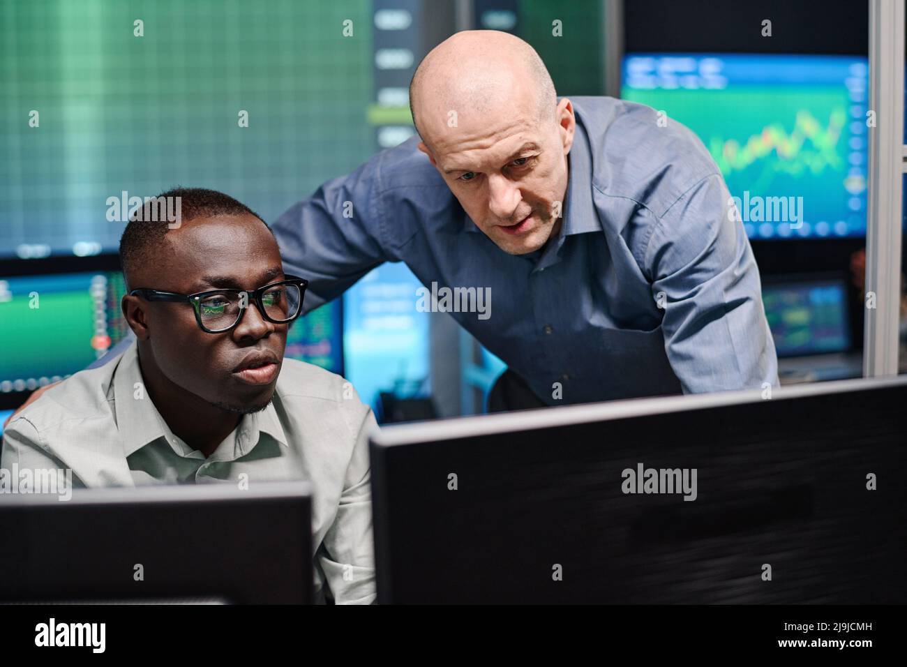 Mature Caucasian man helping new African American employee to analyze ...