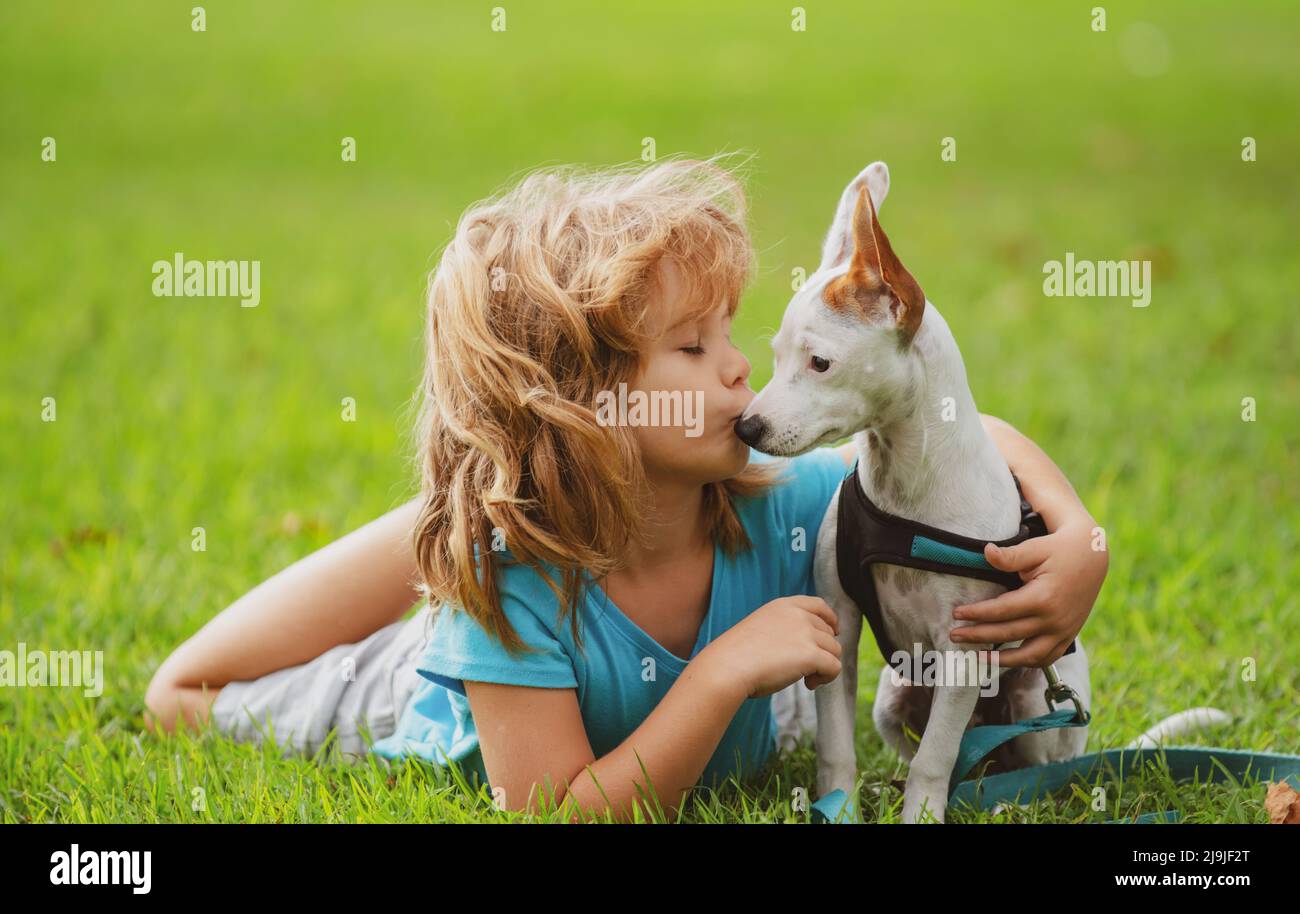 Smiling owner child lying lawn with pet doggy. Happy kid playing with ...