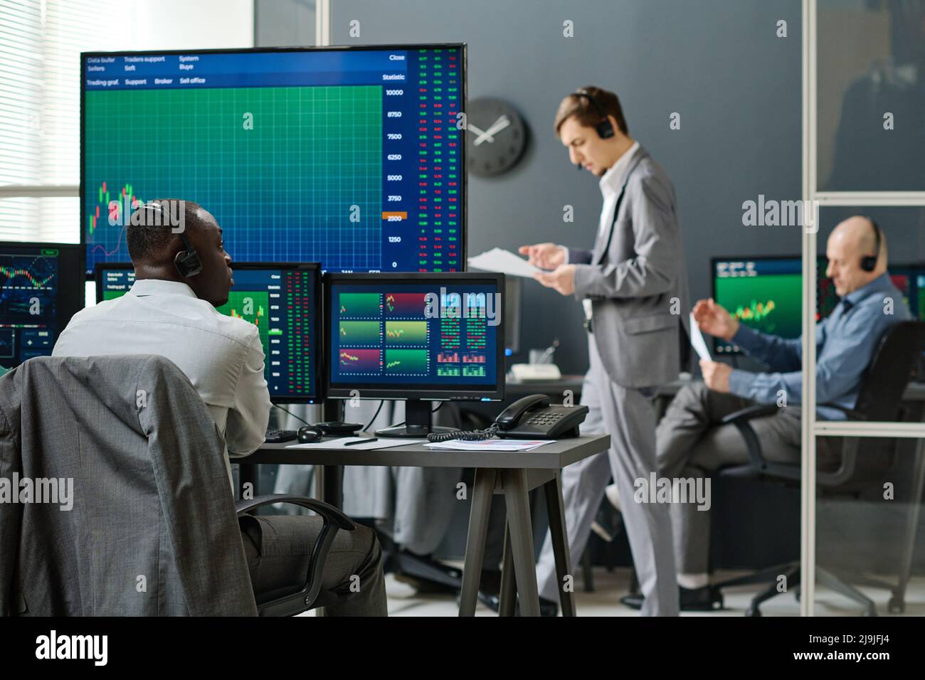 African American and Caucasian men analyzing stock trading stats, having phone calls with ...