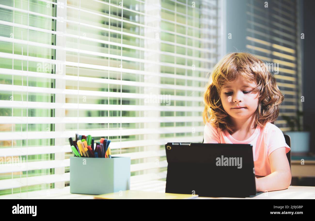 Cute kid boy using tablet on desk at home. Online education concept ...