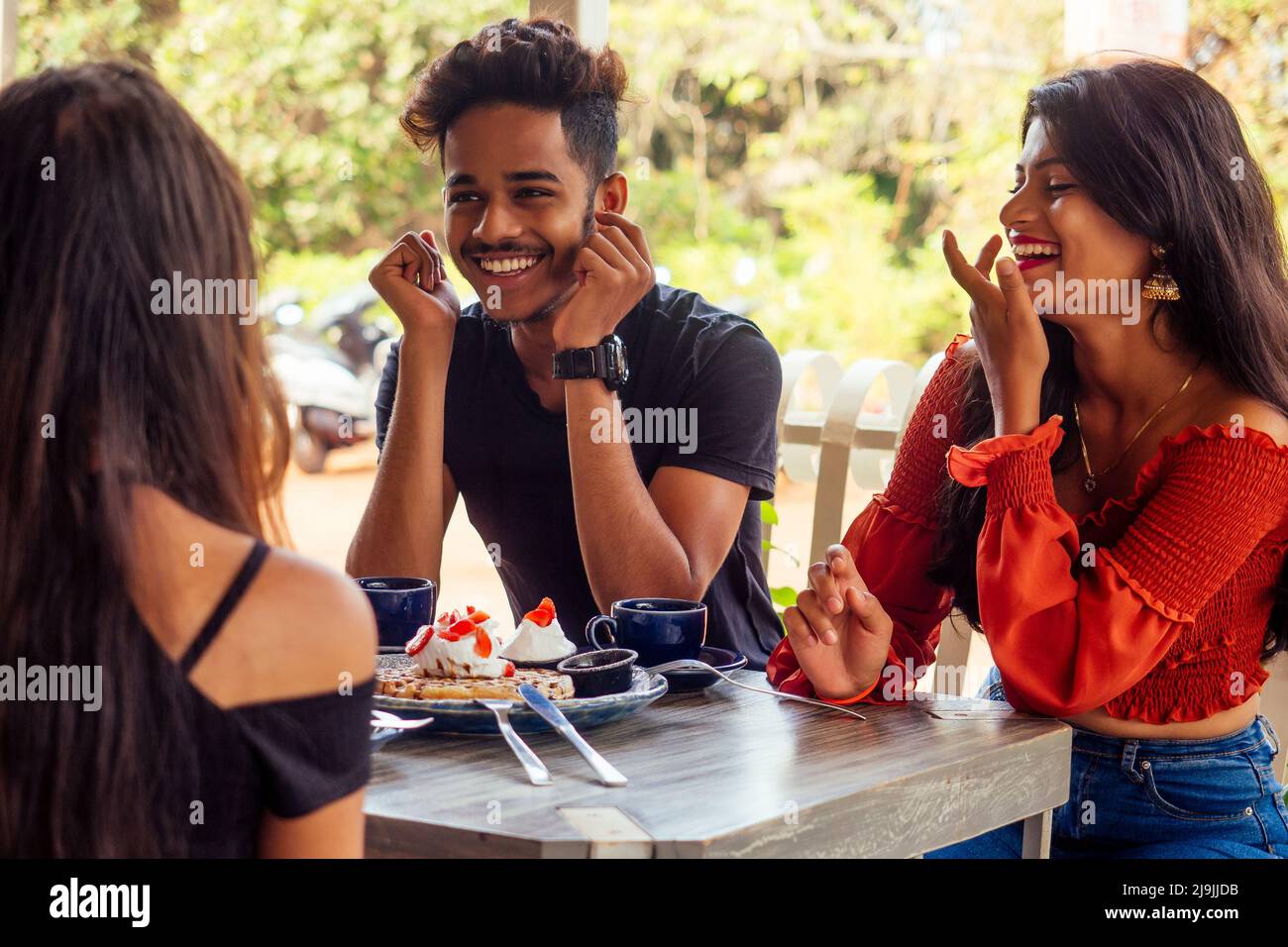 three indian beat Friends eating Sweets pancakes with masala tea in ...