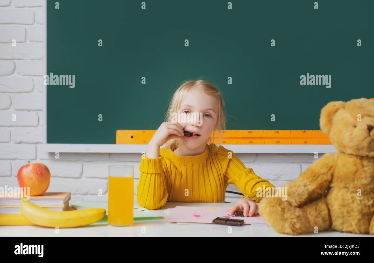 Little school girl student eating chocolate in class, study english ...