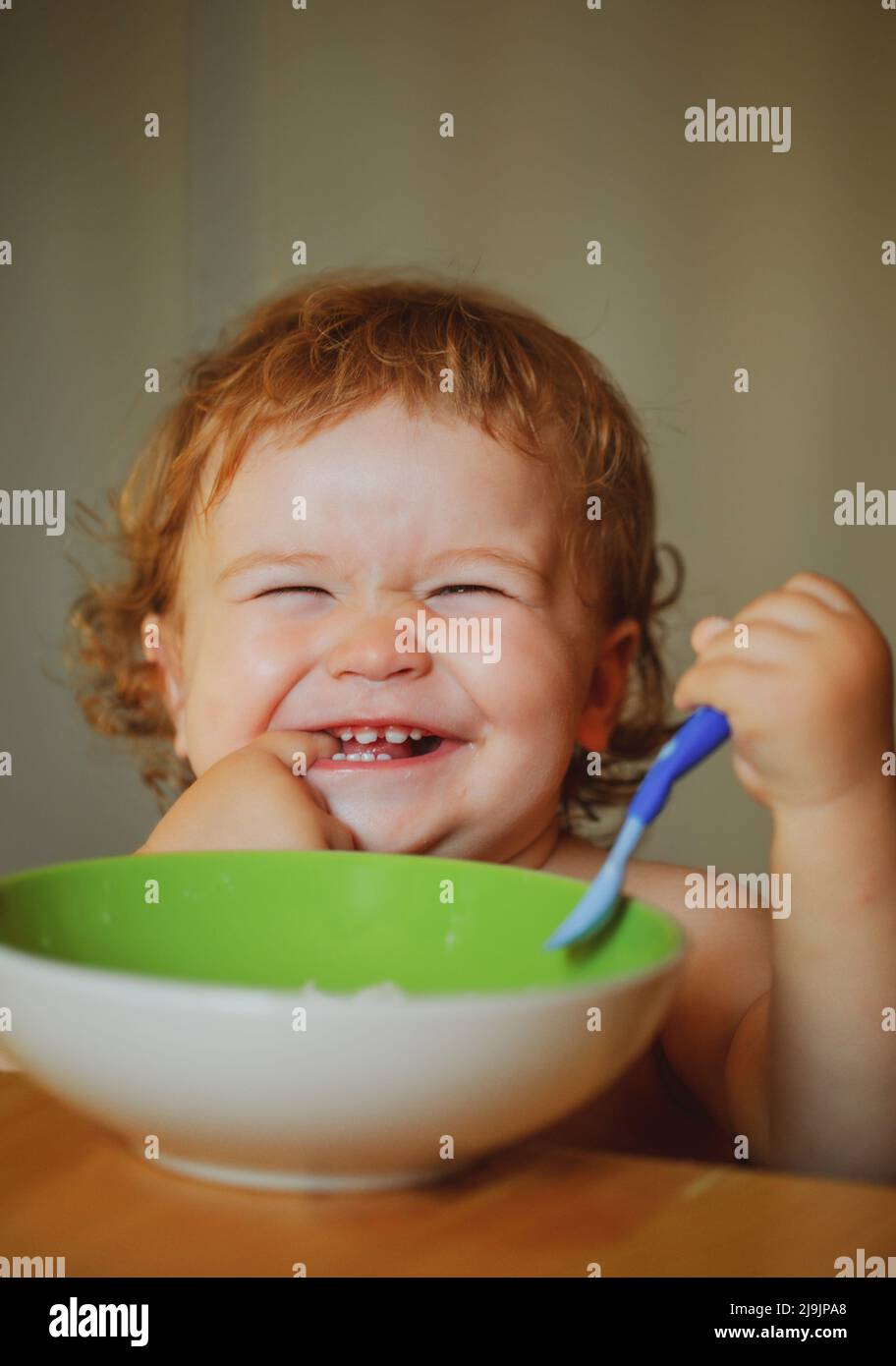 Smiling baby eating food. Launching child with spoon Stock Photo - Alamy