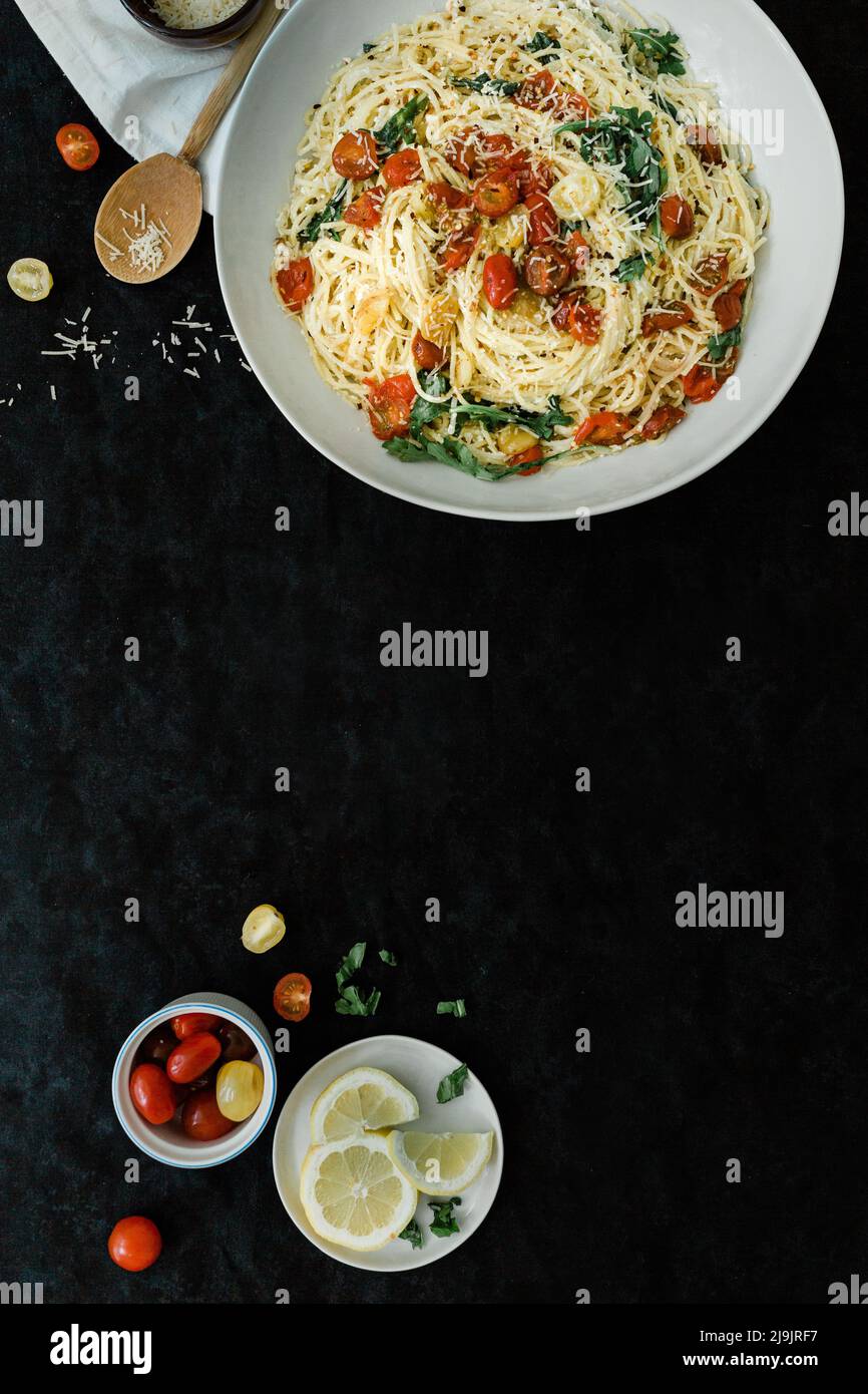 Spaghetti pasta on a wooden dinner table with white plates and napkins ...