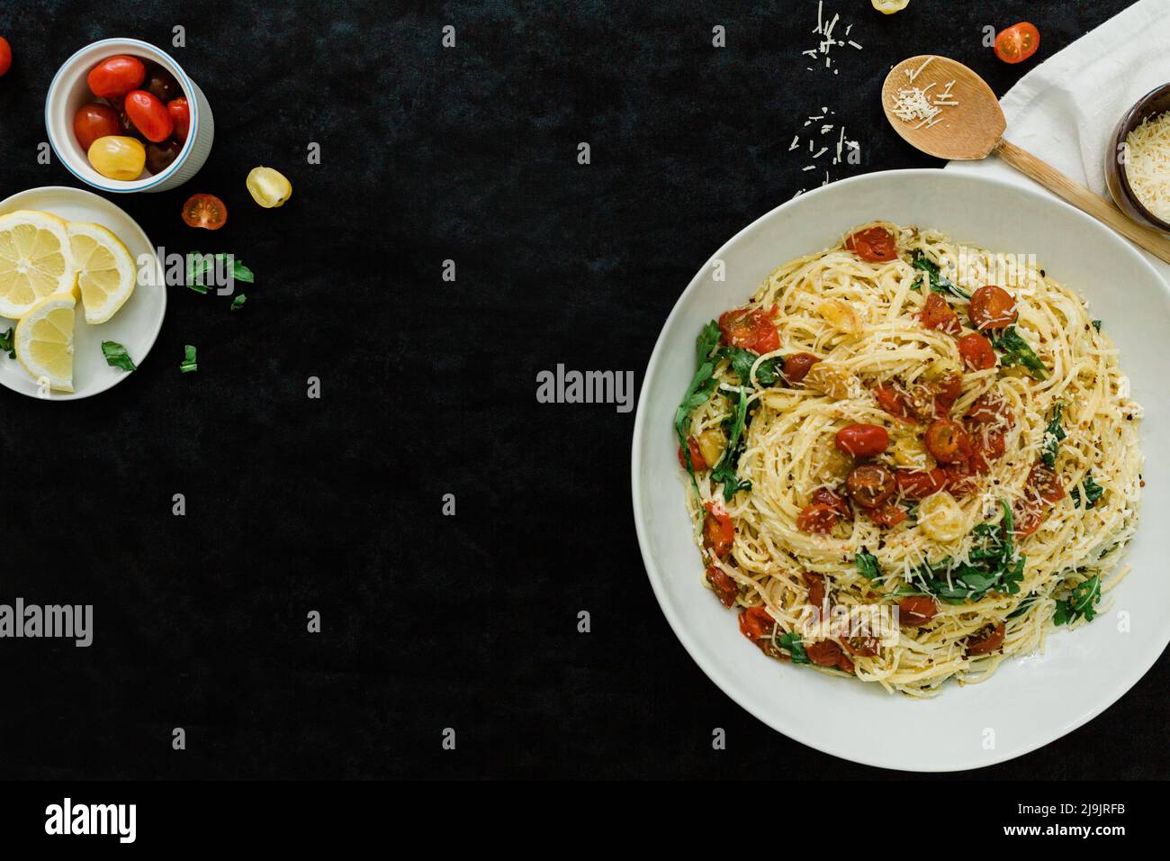 Spaghetti pasta on a wooden dinner table with white plates and napkins ...