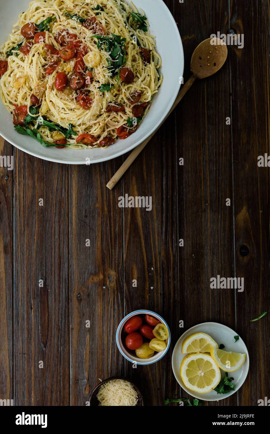 Spaghetti pasta on a wooden dinner table with white plates and napkins ...