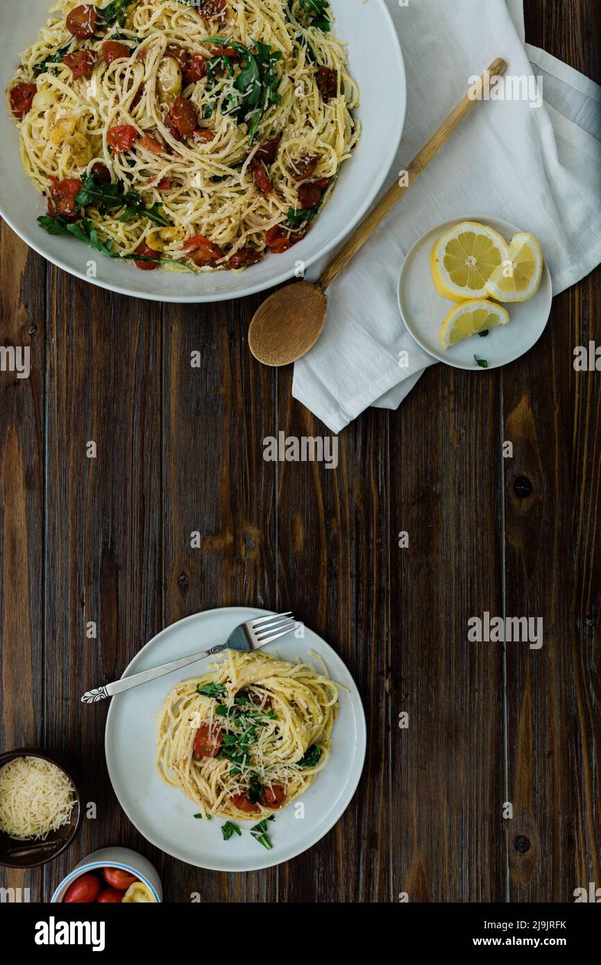 Spaghetti pasta on a wooden dinner table with white plates and napkins ...