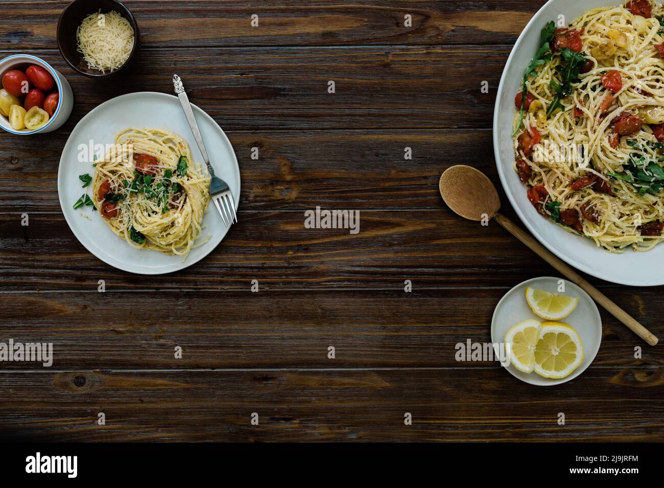 Spaghetti pasta on a wooden dinner table with white plates and napkins ...