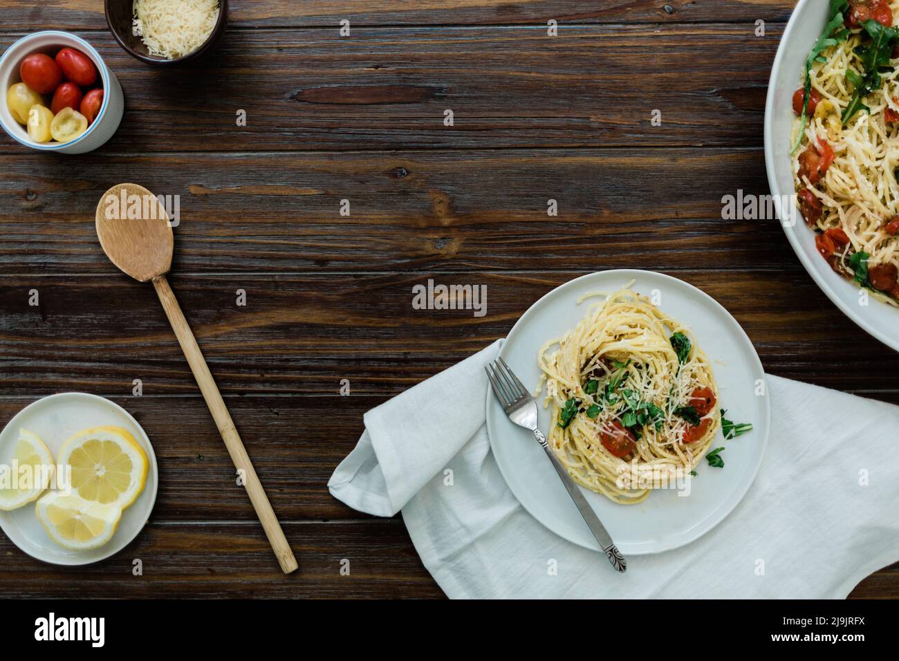 Spaghetti pasta on a wooden dinner table with white plates and napkins ...