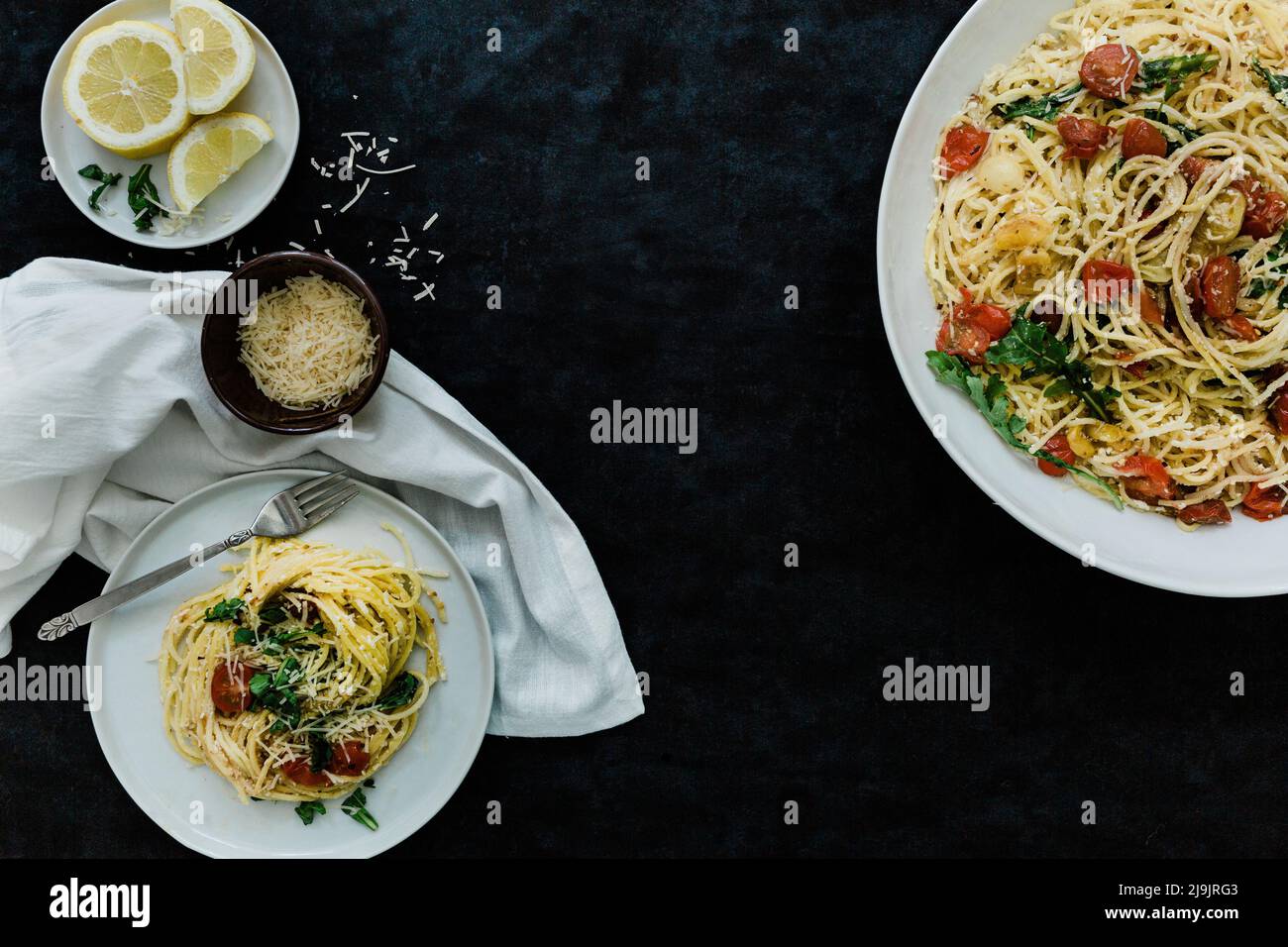 Spaghetti pasta on a wooden dinner table with white plates and napkins ...