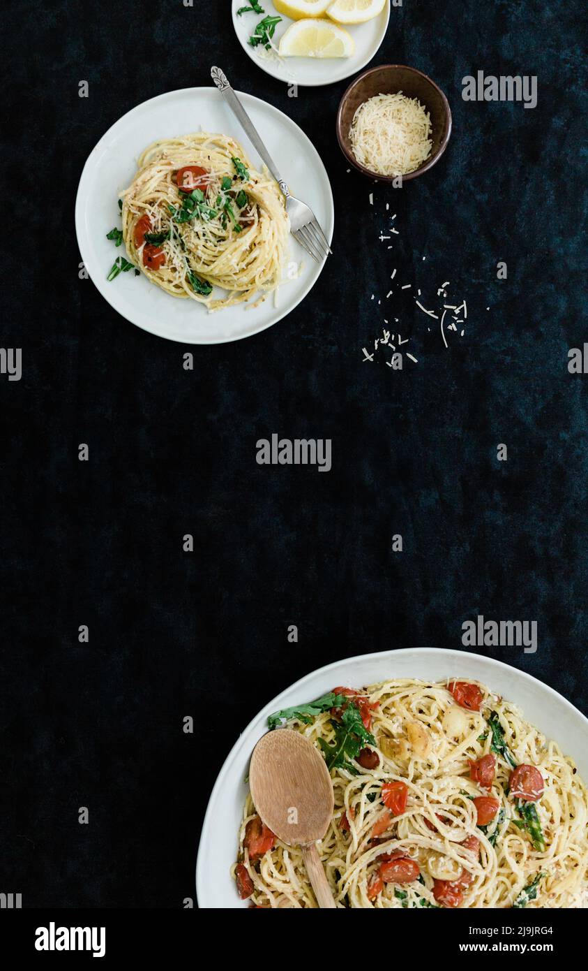 Spaghetti pasta on a wooden dinner table with white plates and napkins ...
